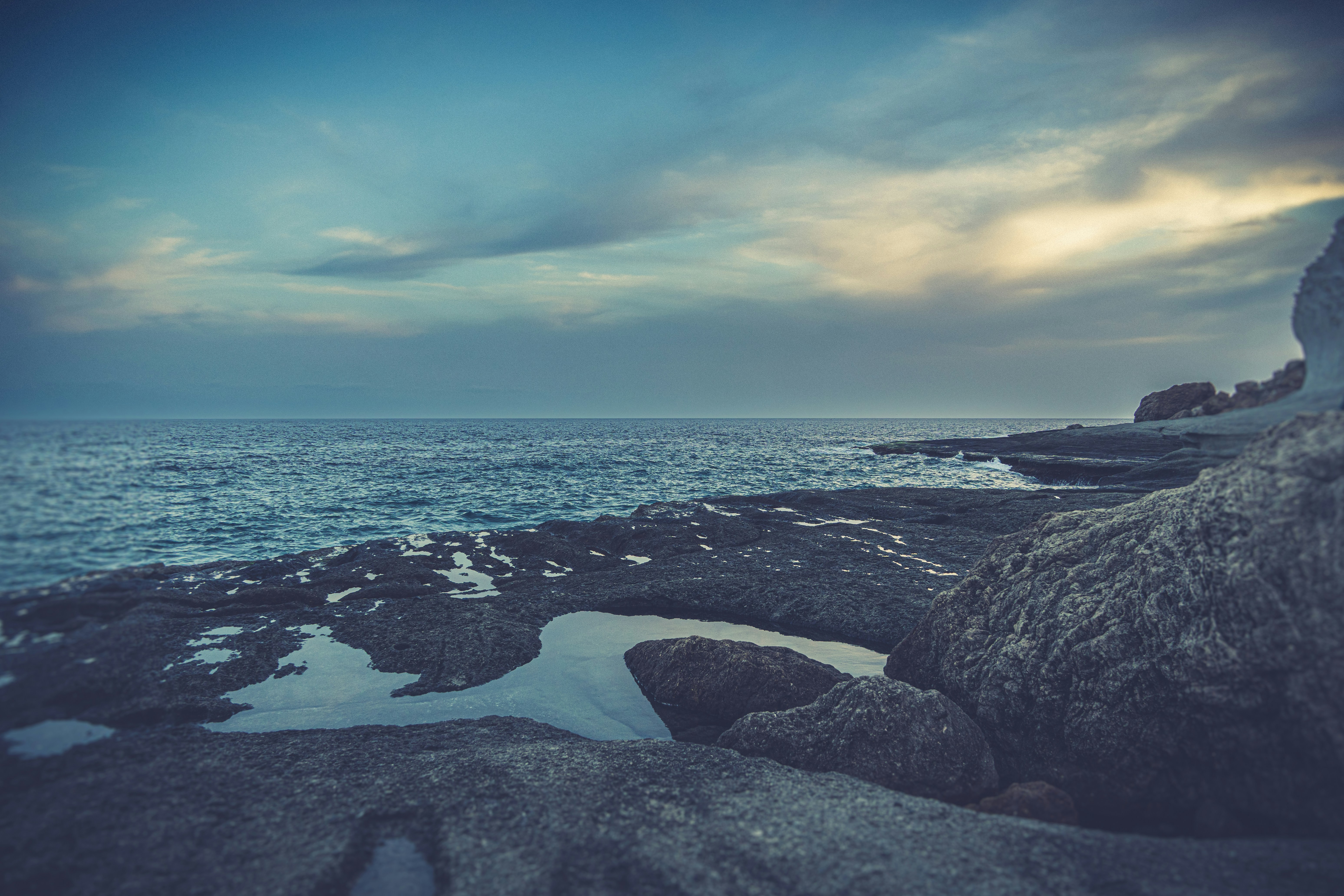 Coastal Silhouette at Dusk: Rugged Rocks Meeting the Quiet Sea