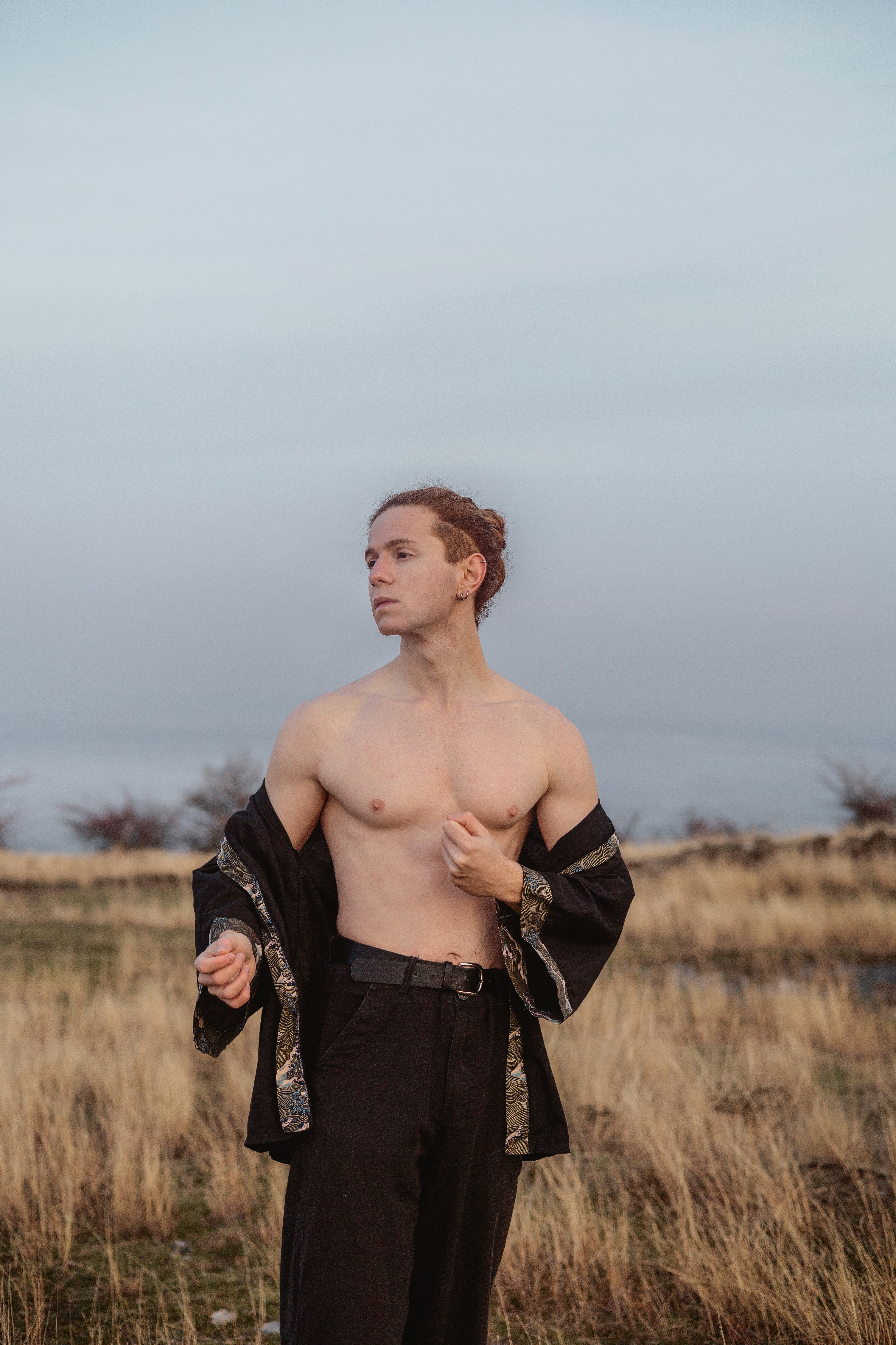 Portrait in the Meadow: A Shirtless Figure in Ceremonial Black Opens Up the Horizon