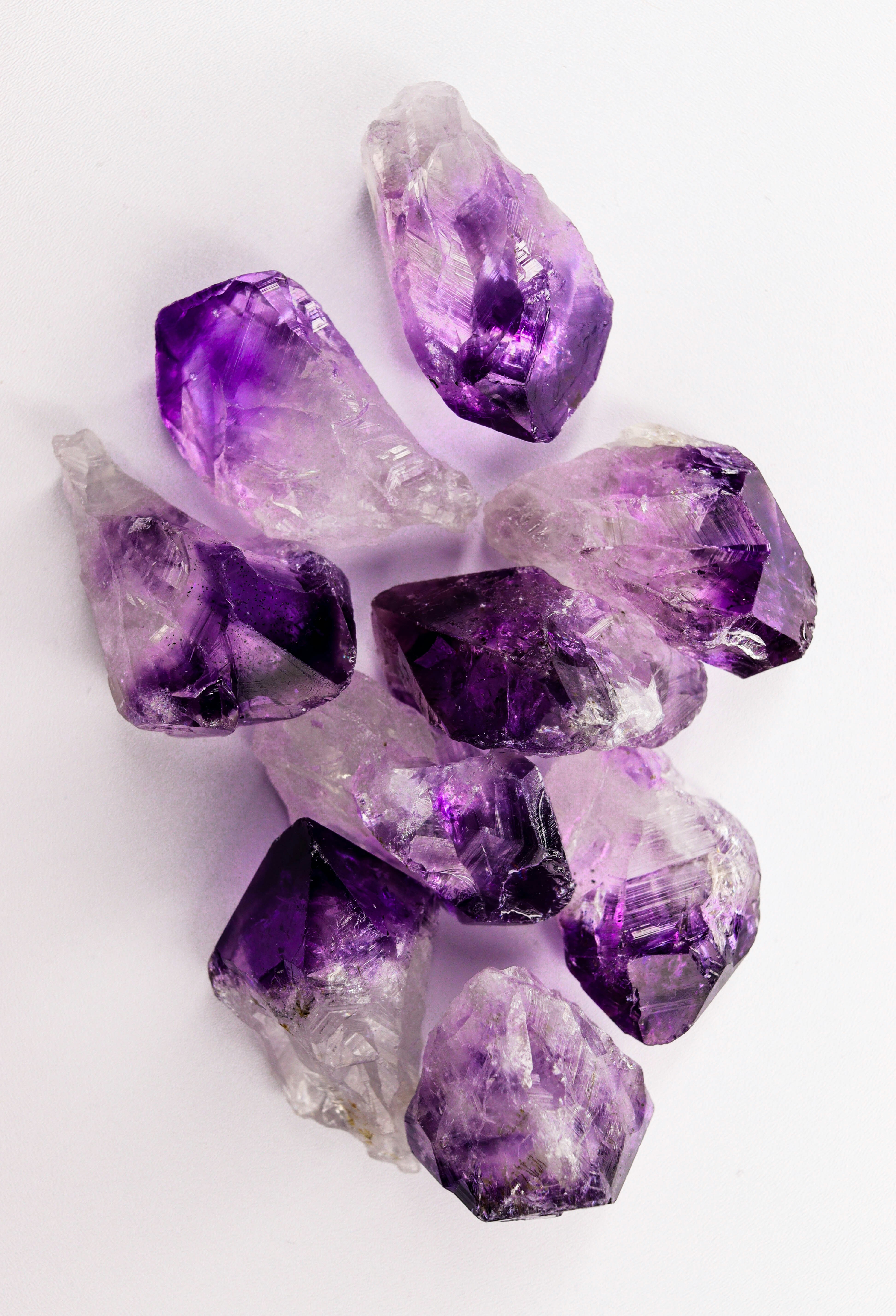 Raw amethyst crystals scattered on a white background.