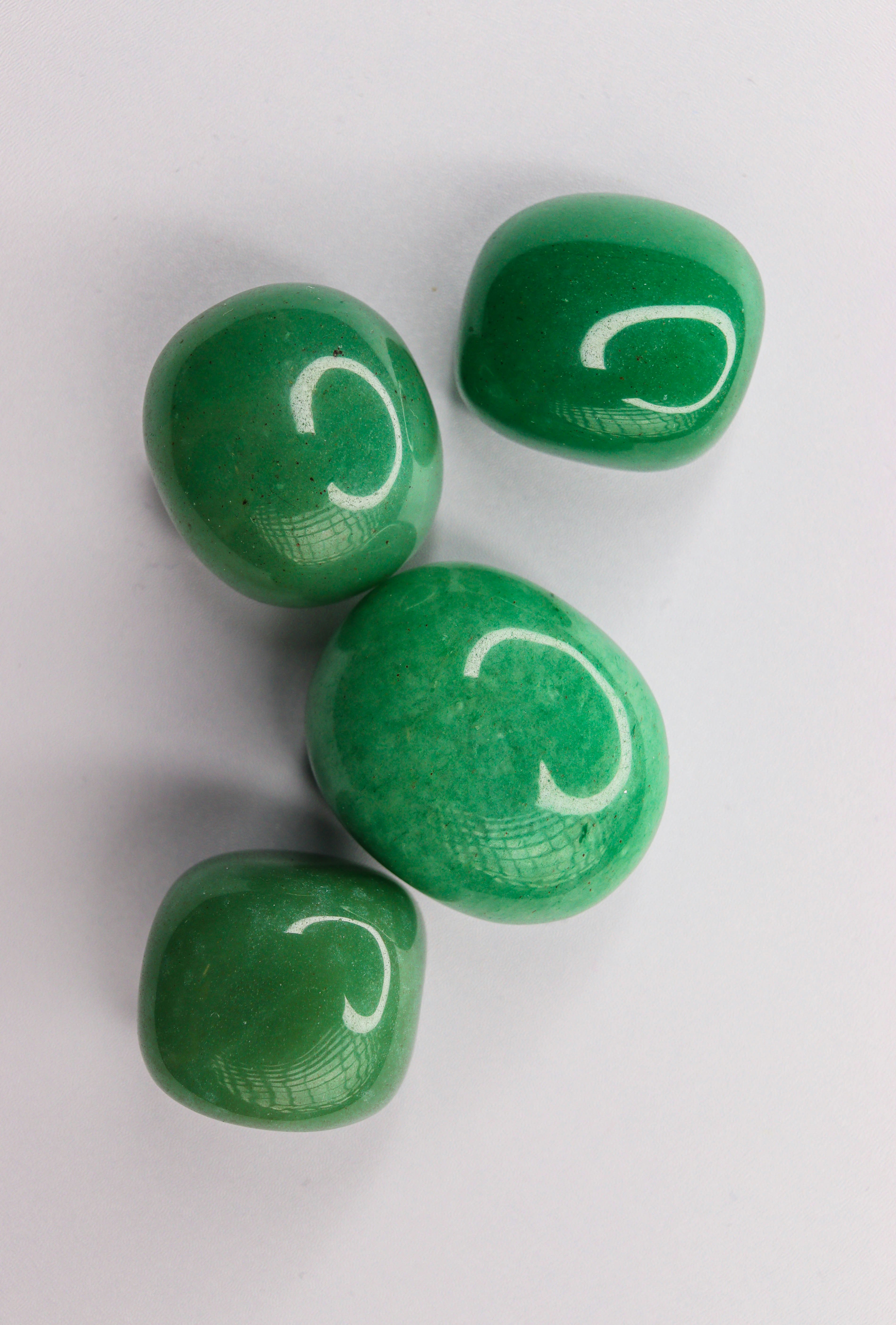 Verdant Pebbles: A Cluster of Green Glassy Orbs on White