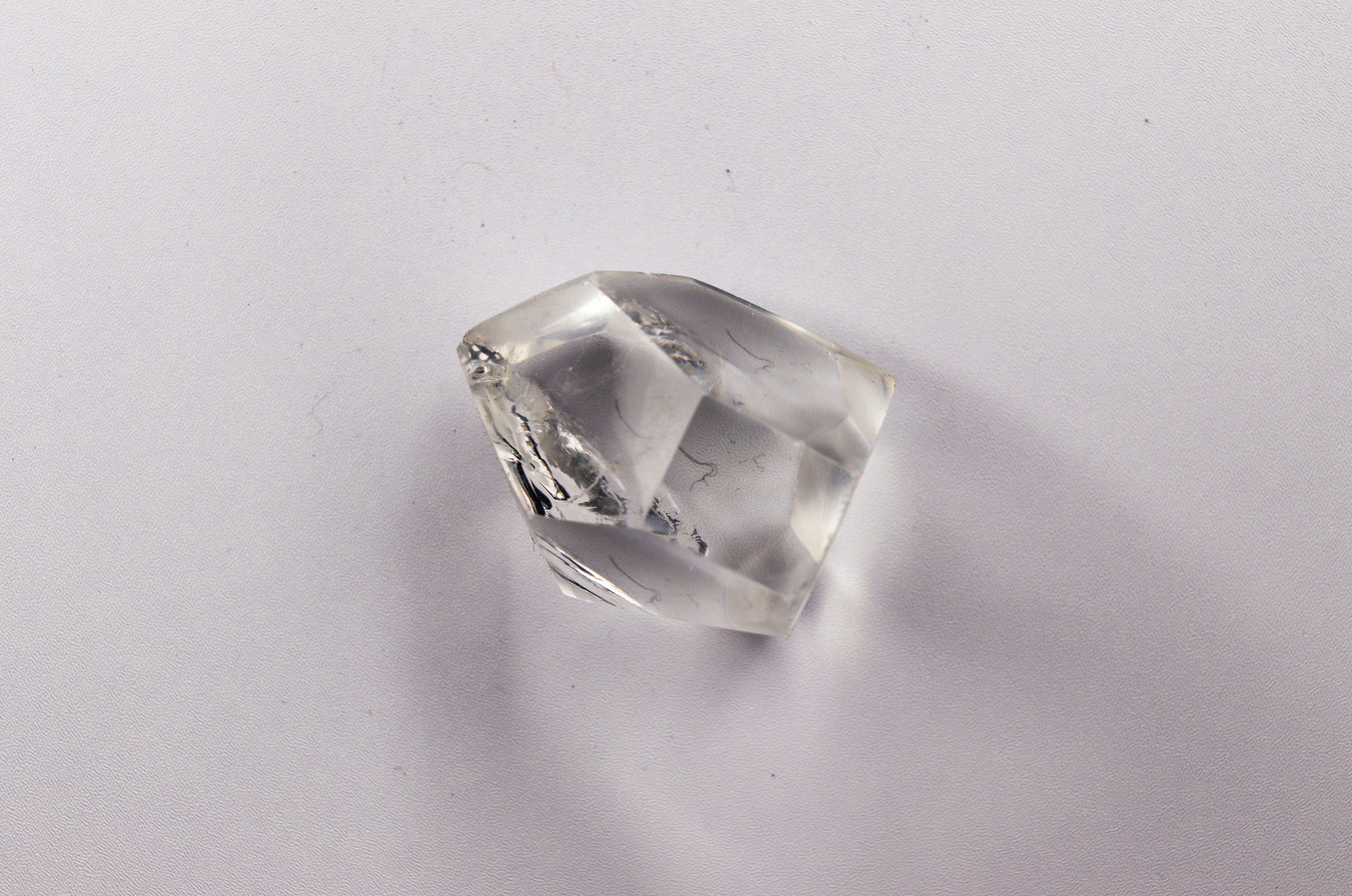 A clear, uncut diamond crystal on a white background.