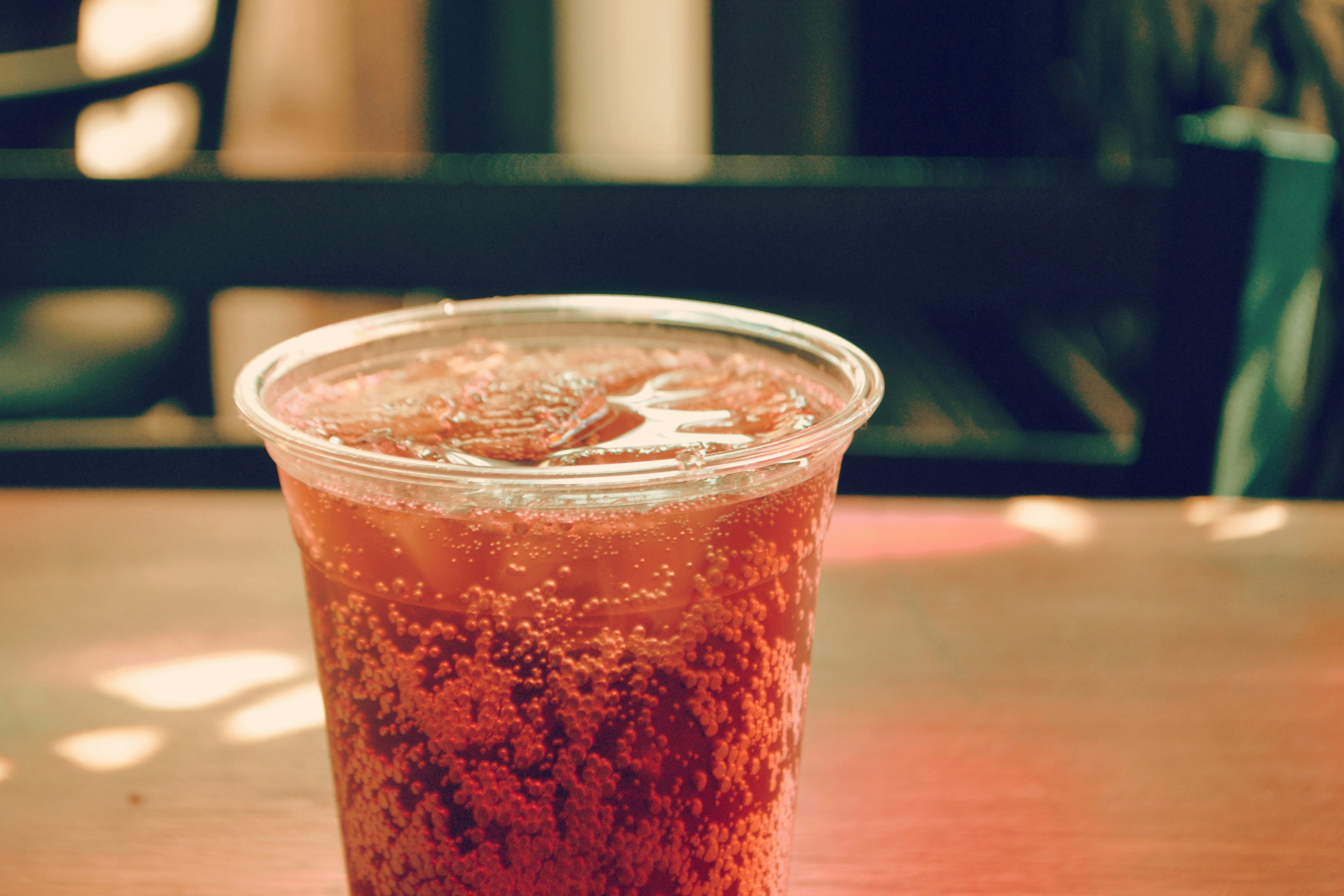 A plastic cup filled with a bubbly reddish-brown drink.