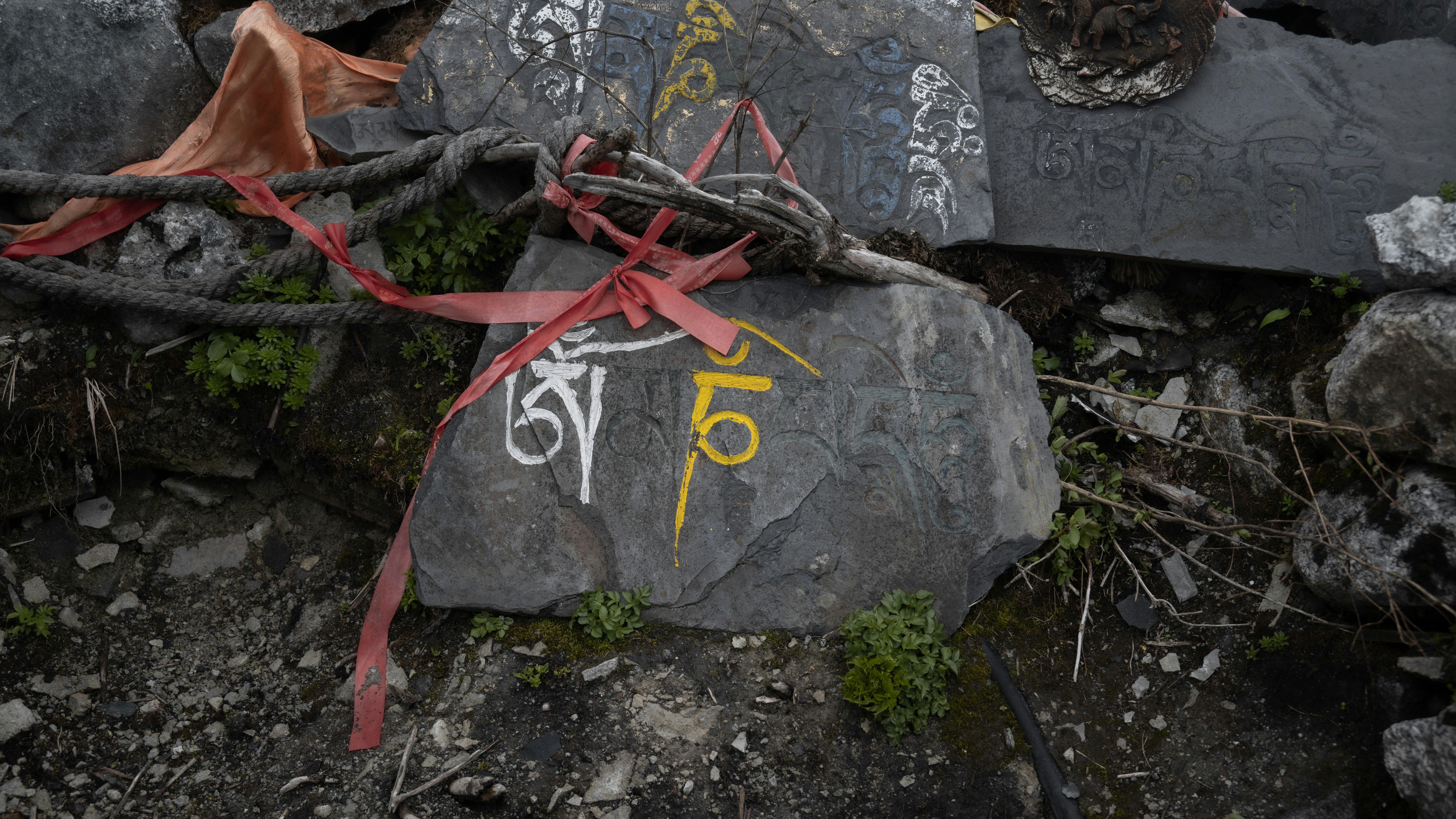 A rock with painted spiritual symbols and colorful ribbons.