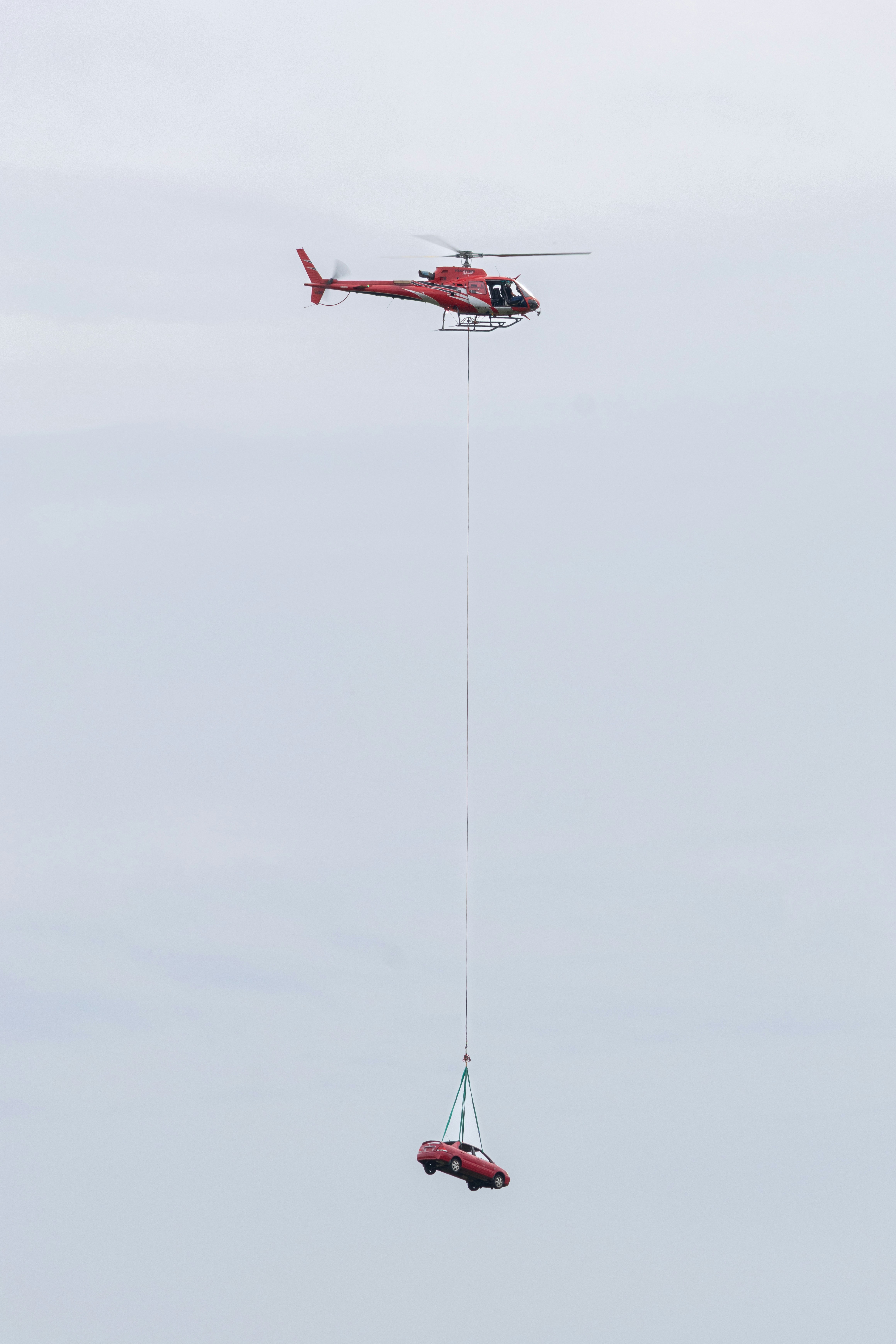 Zipline Lift: Red Helicopter Hoists a Car Across an Open Sky
