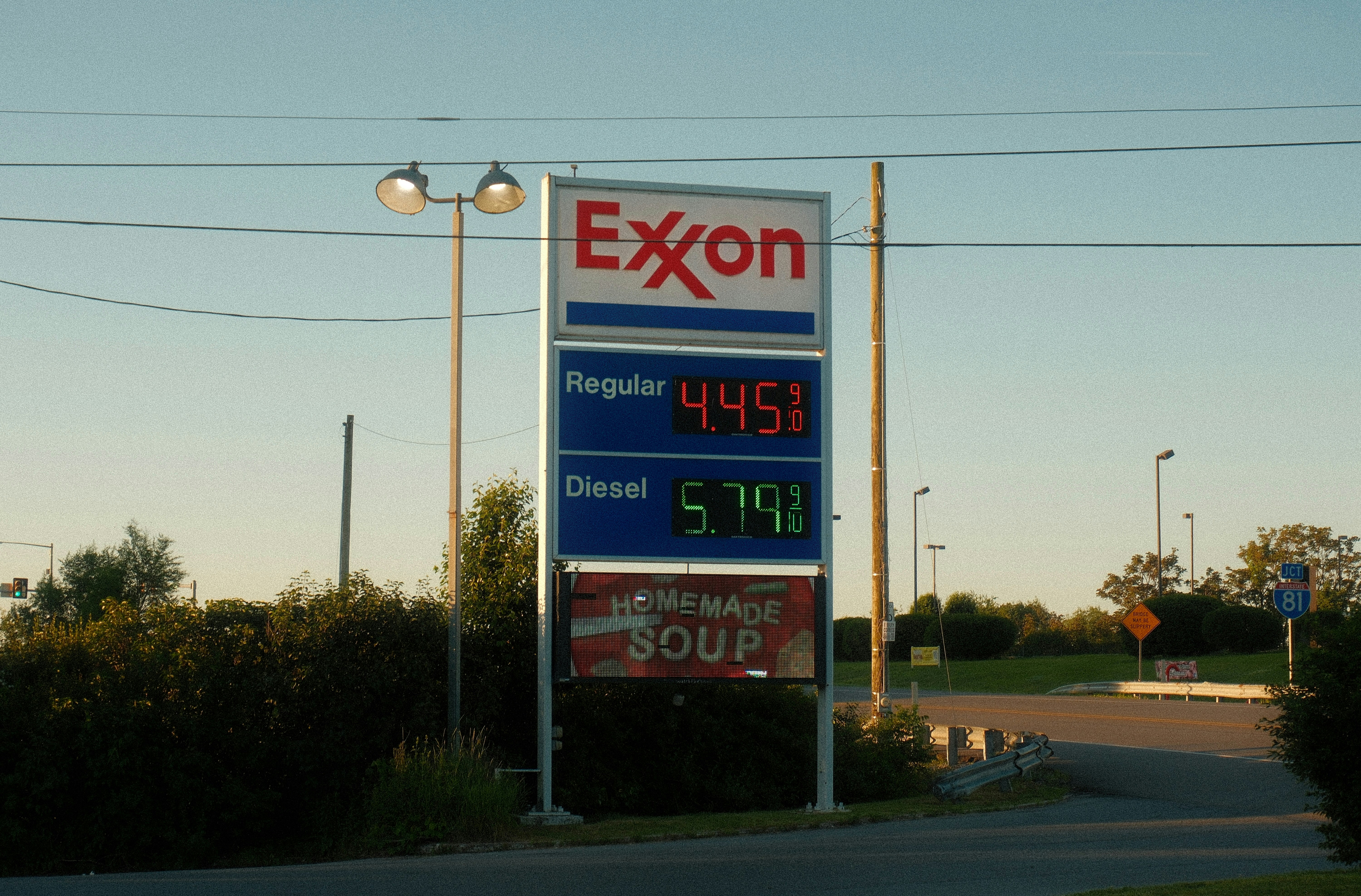 Exxon gas station sign displaying fuel prices and soup advertisement.