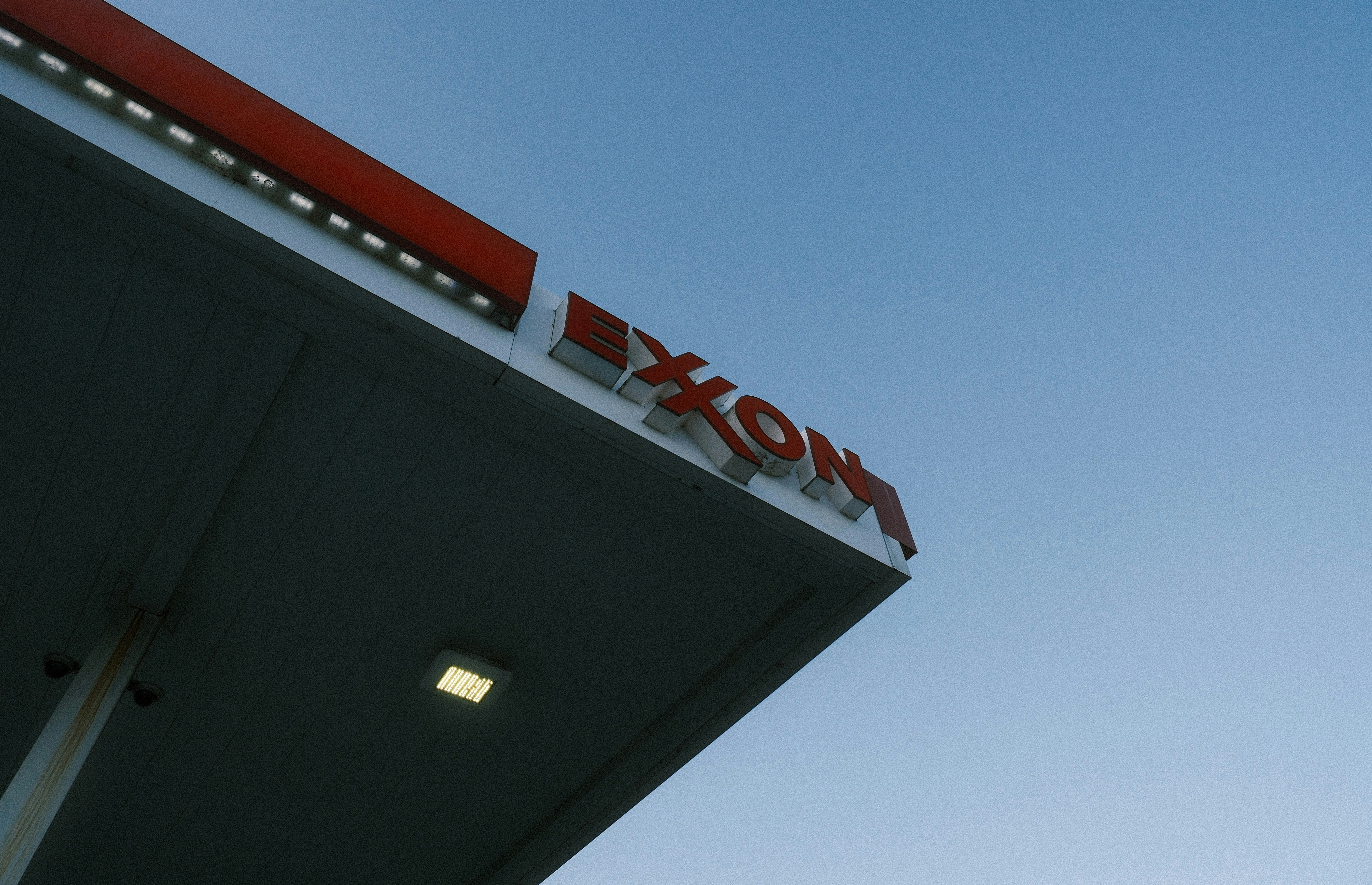 Exxon gas station sign and canopy under blue sky.