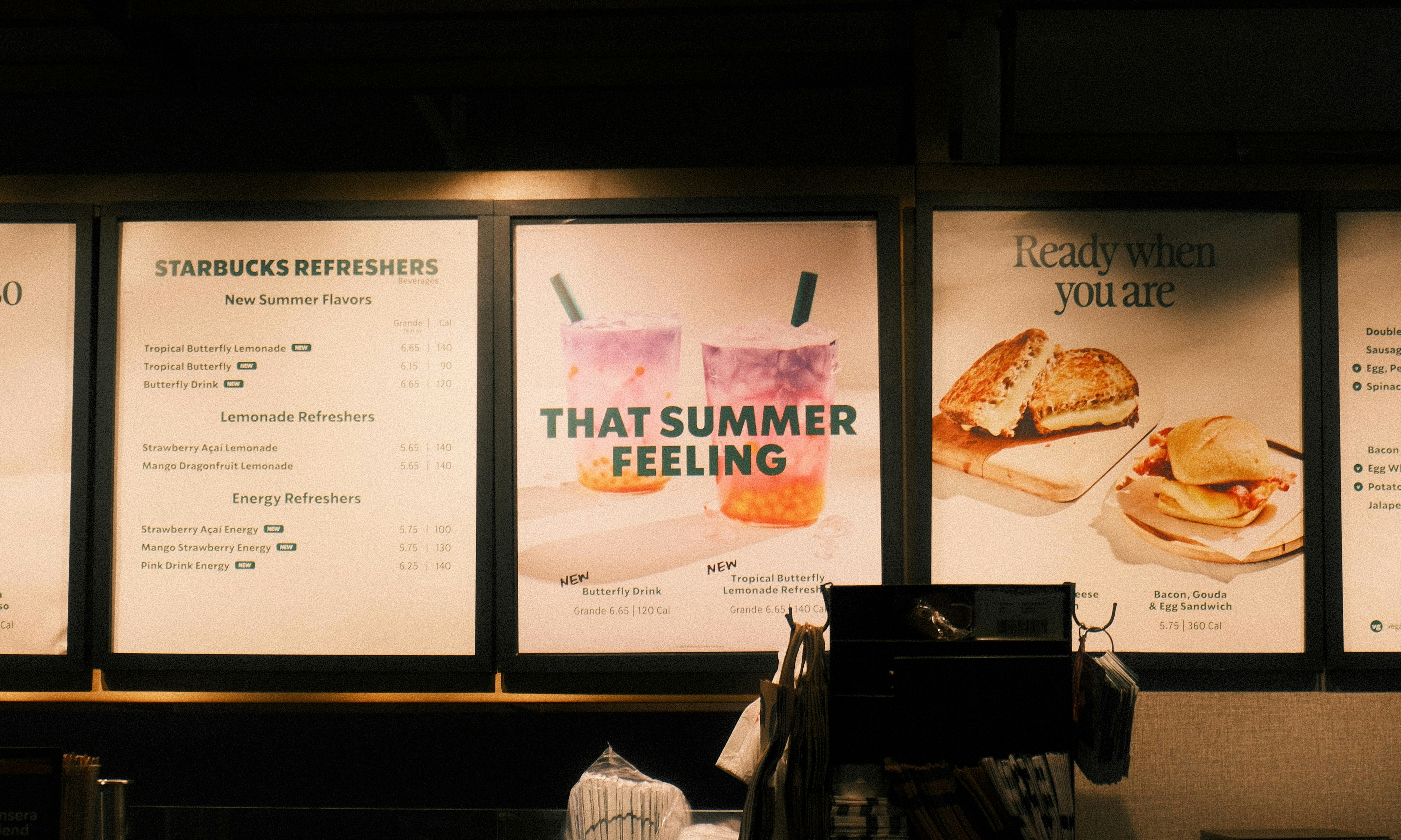 Starbucks menu board displaying beverages and sandwiches.