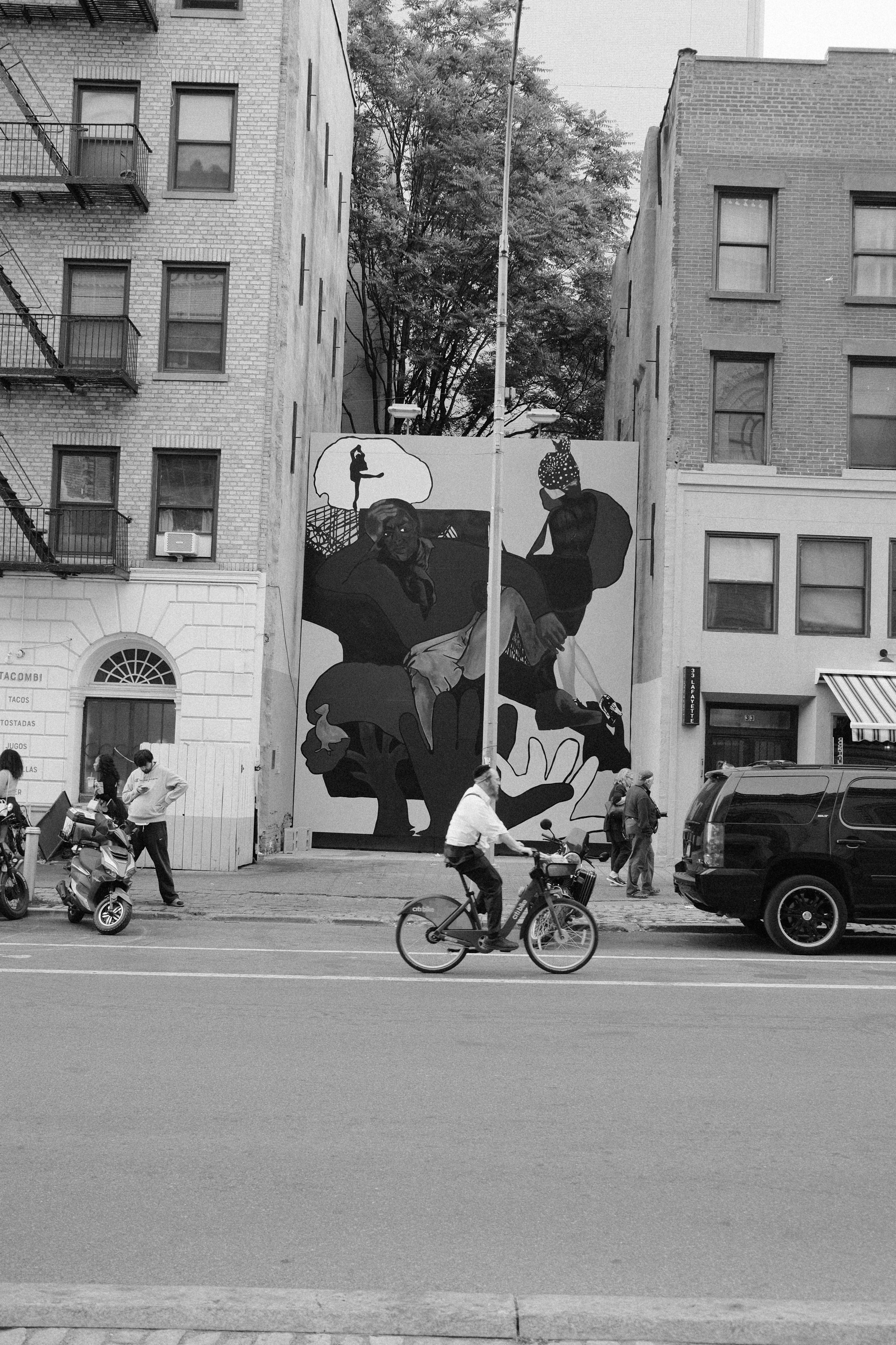 Urban mural and cyclist cadence across a sunlit street
