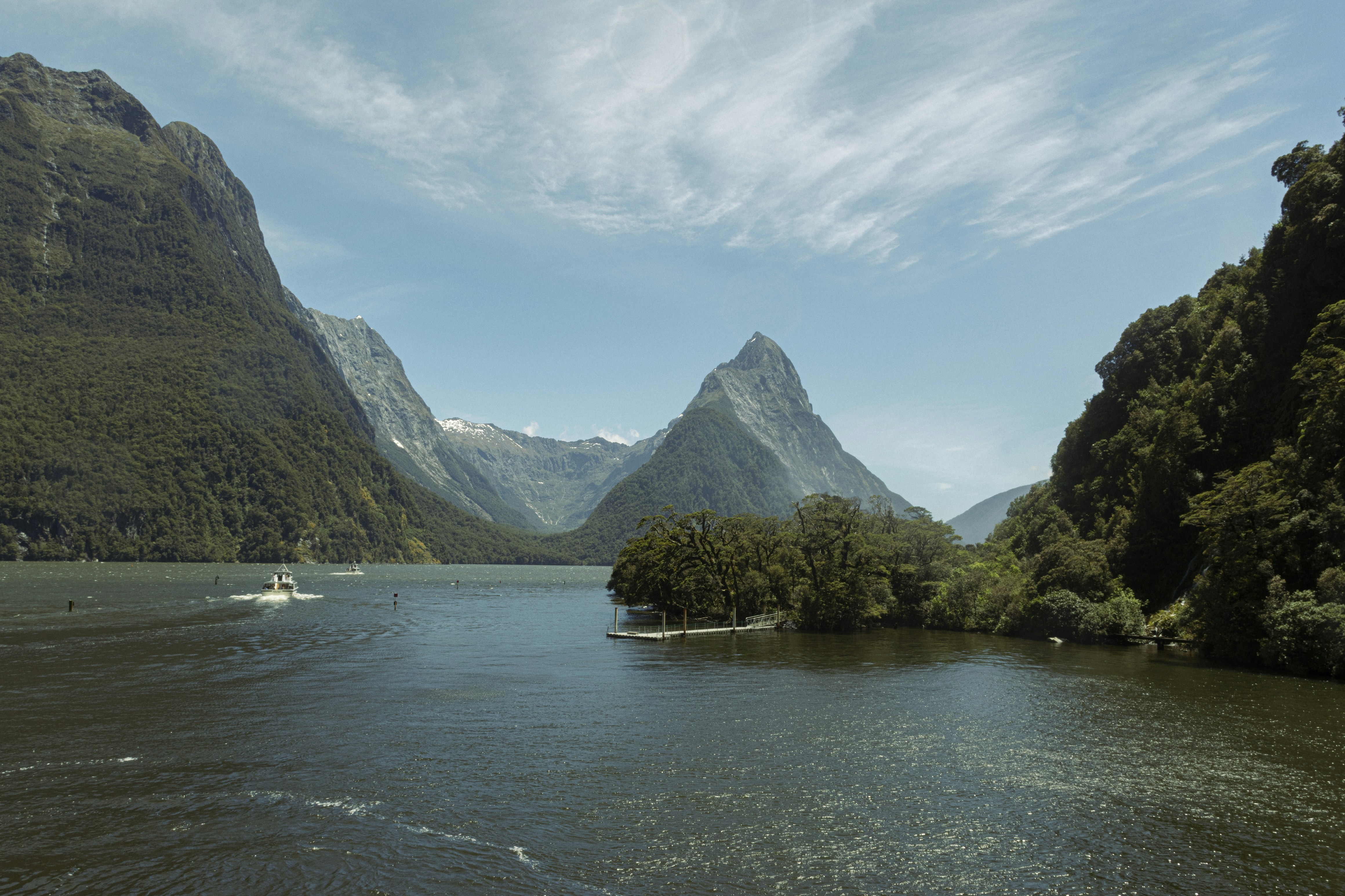 Majestic fjord landscape with towering mountains, water, and a boat.