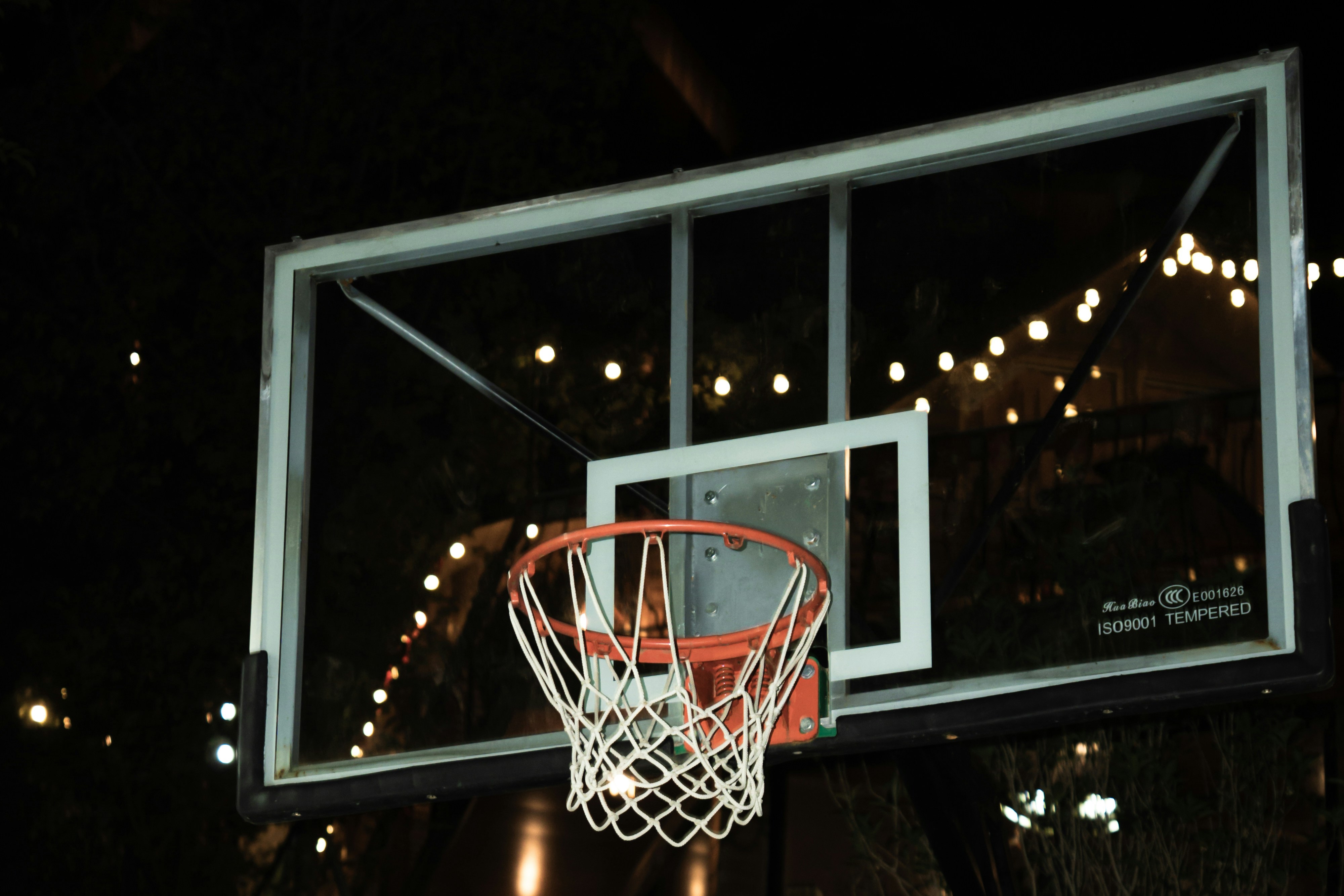 Night game under warm string lights: a lone basketball hoop