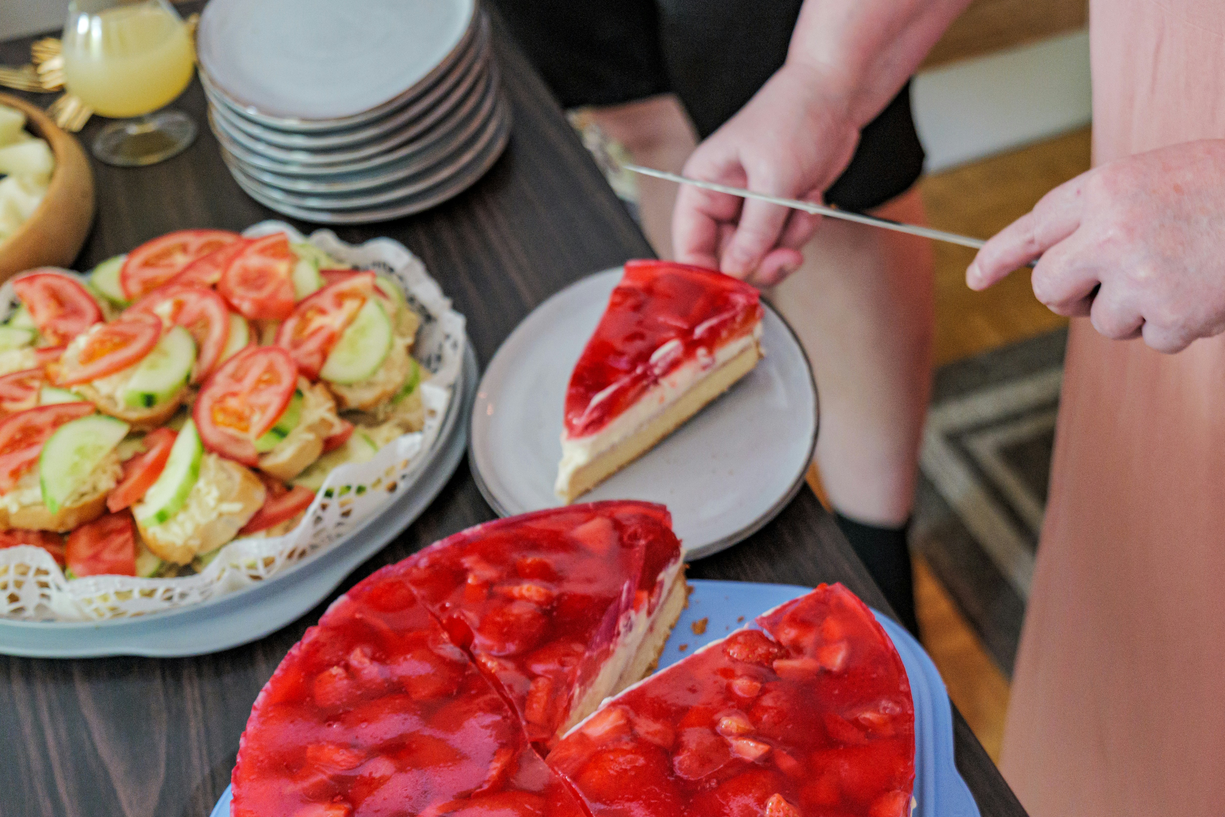 Serving a slice of strawberry cheesecake and savory snacks.
