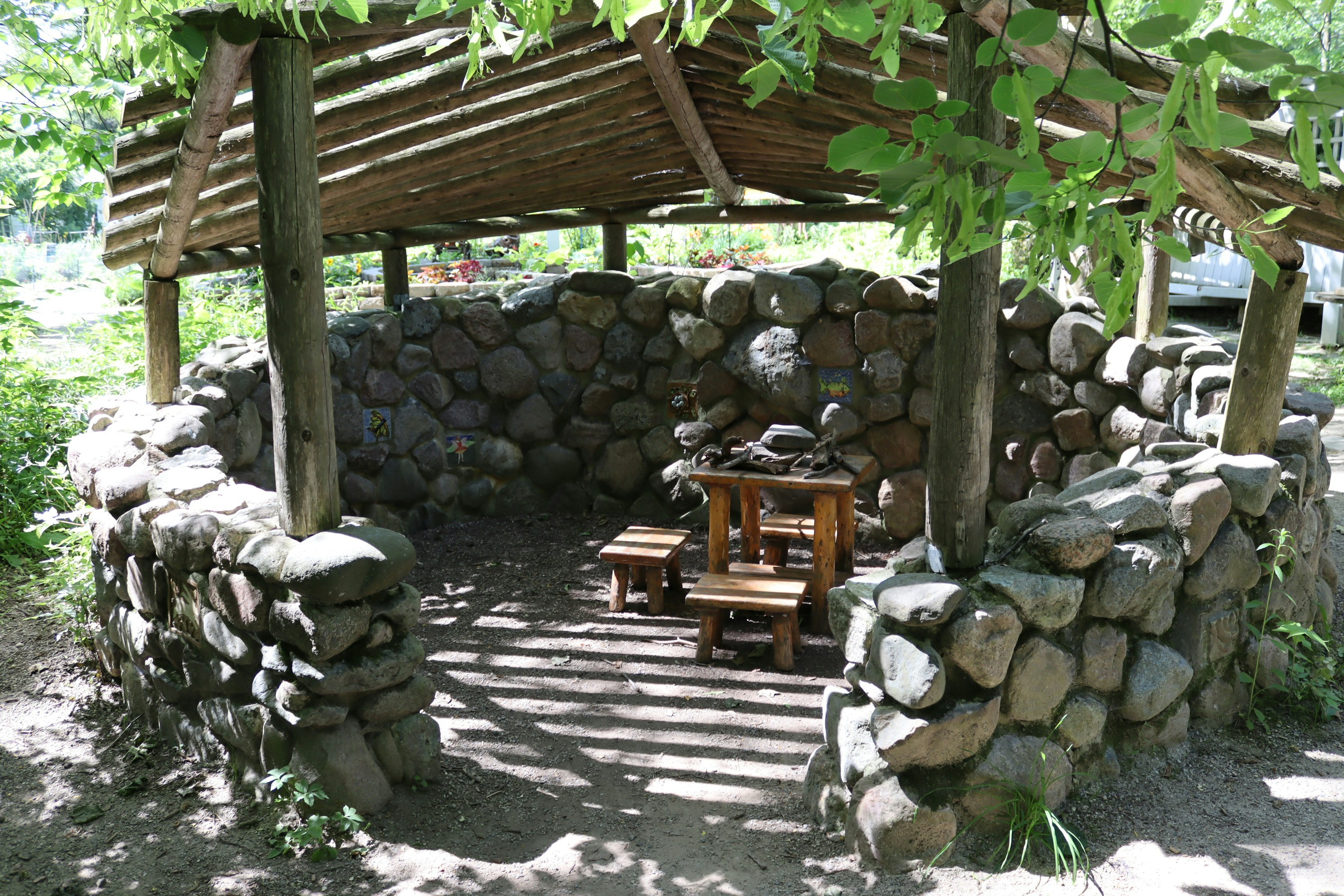 Rustic stone and wood shelter with table and benches.