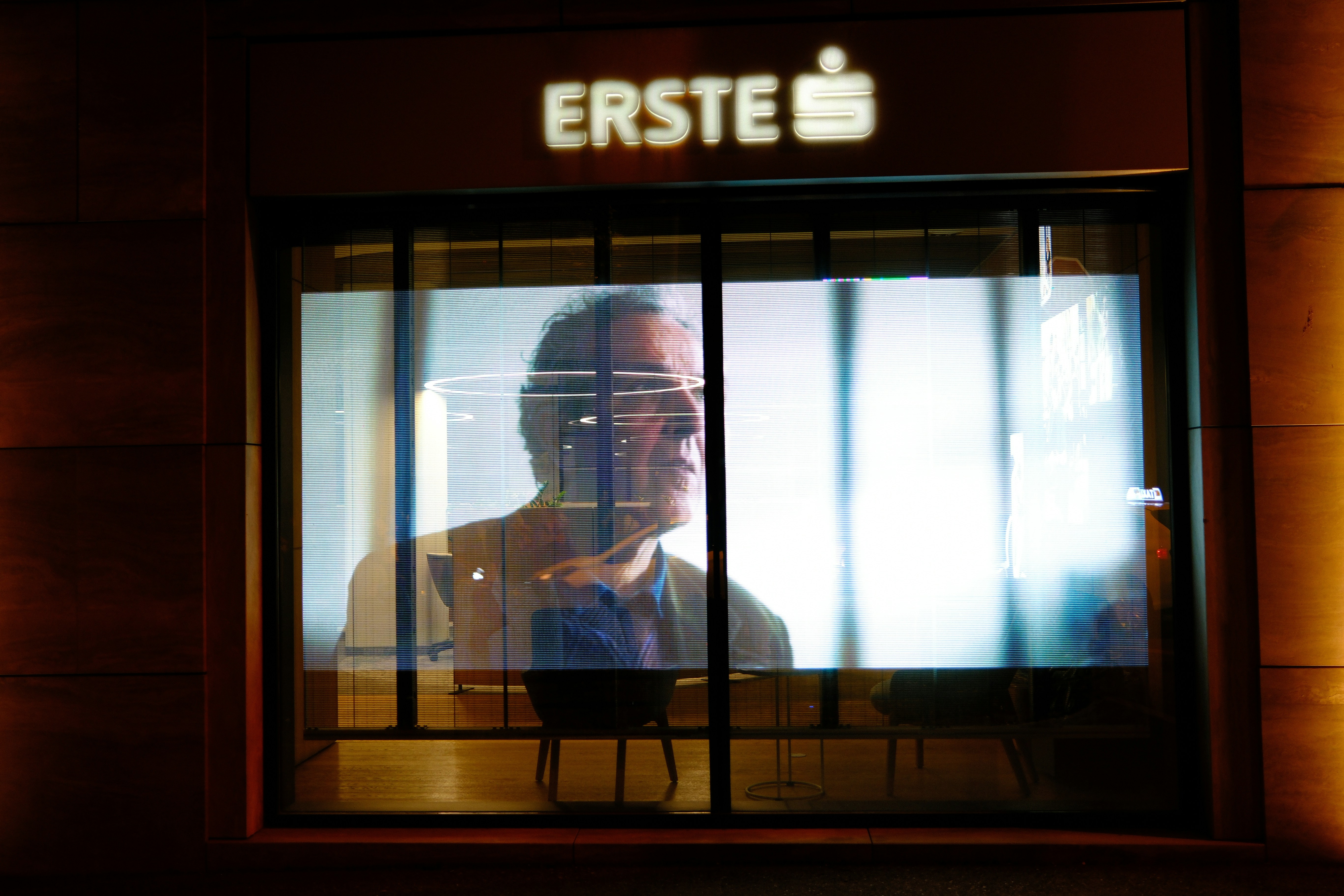 A man's face visible through erste bank window.