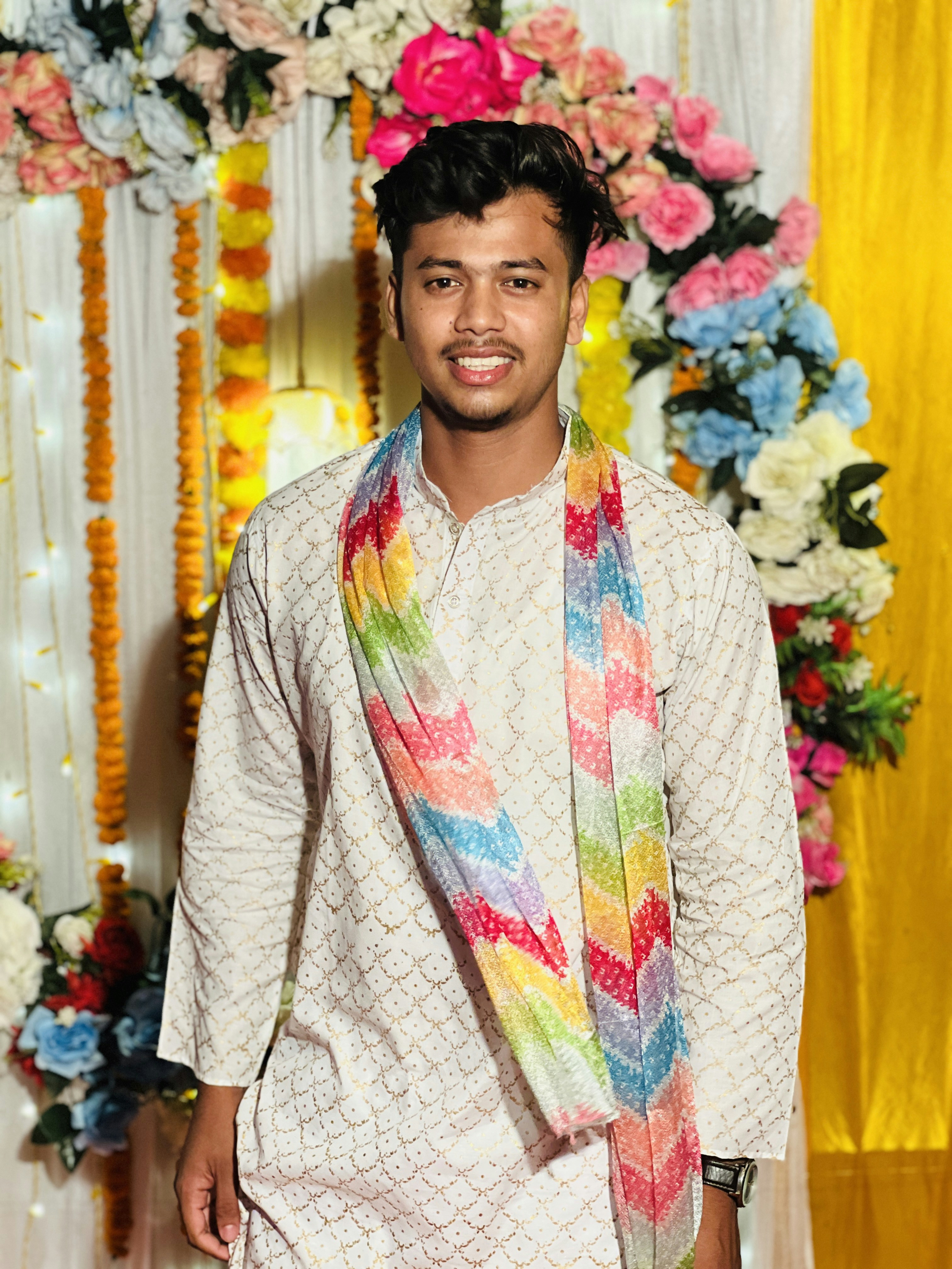Smiling young man in traditional kurta and colorful scarf.