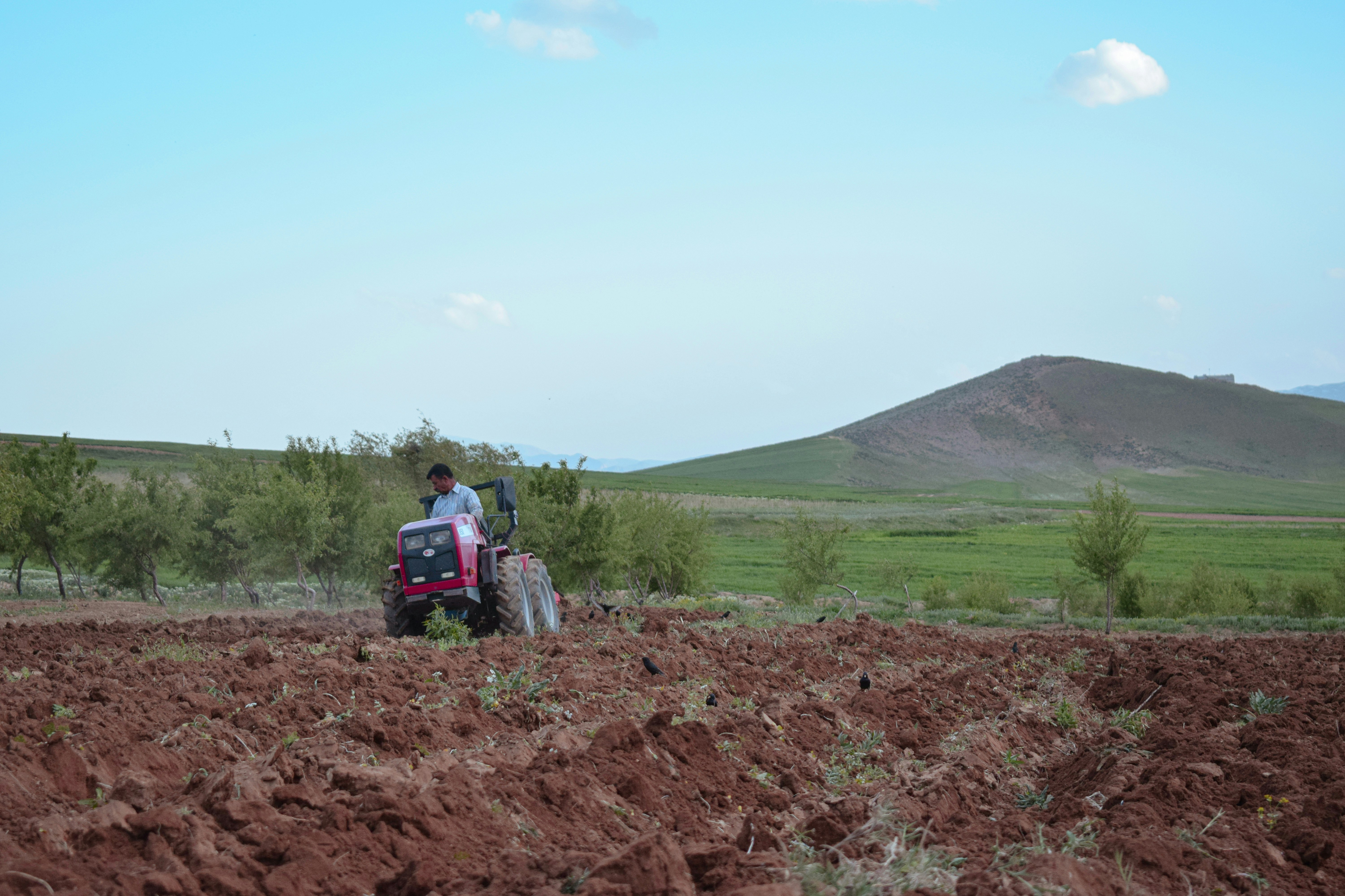 Tractor at the Edge of Parched Red Earth under a Wide Blue Sky