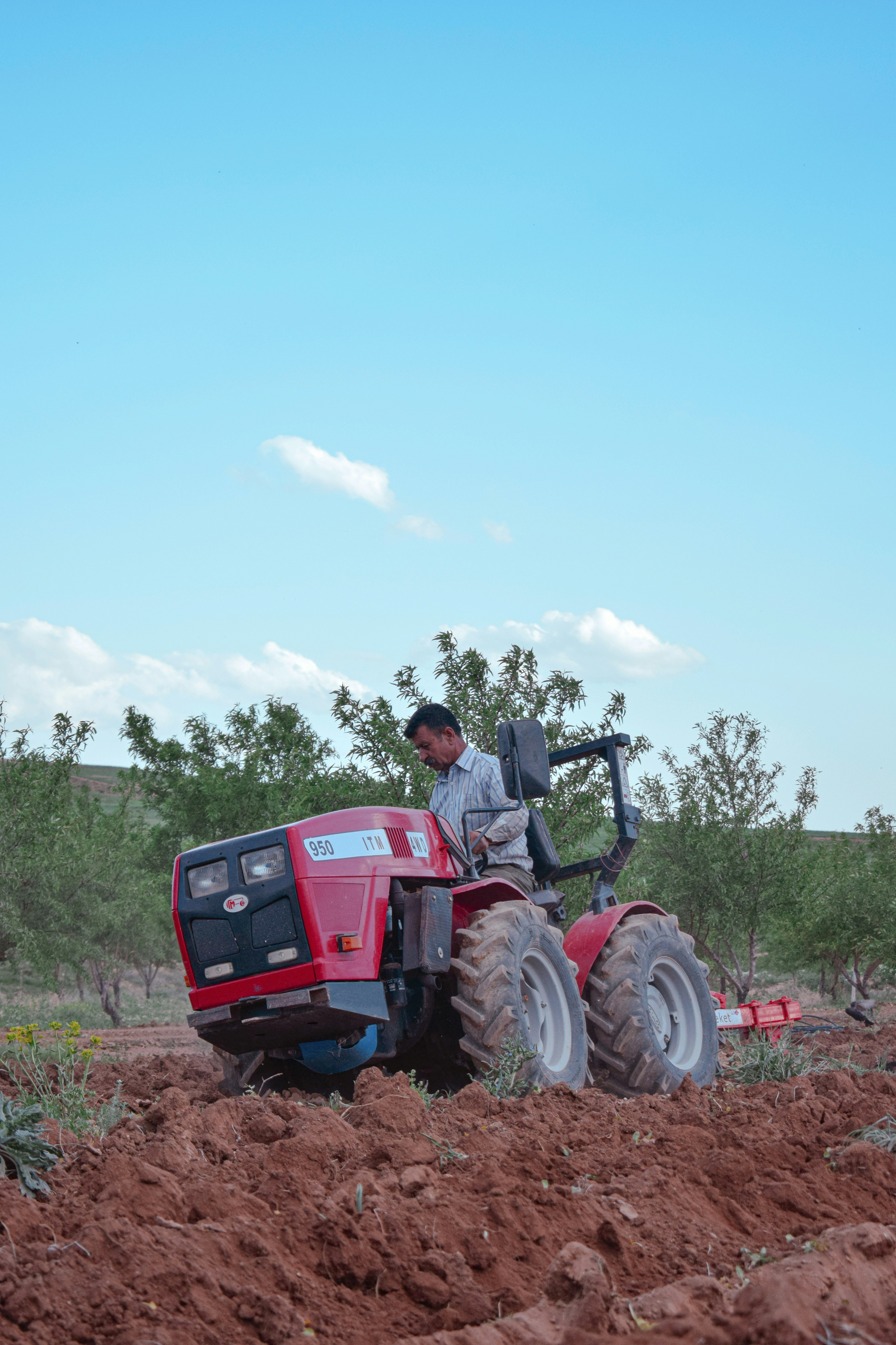 Red Tractor in Rough Soil: A Farmer’s Workday Beneath an Open Sky