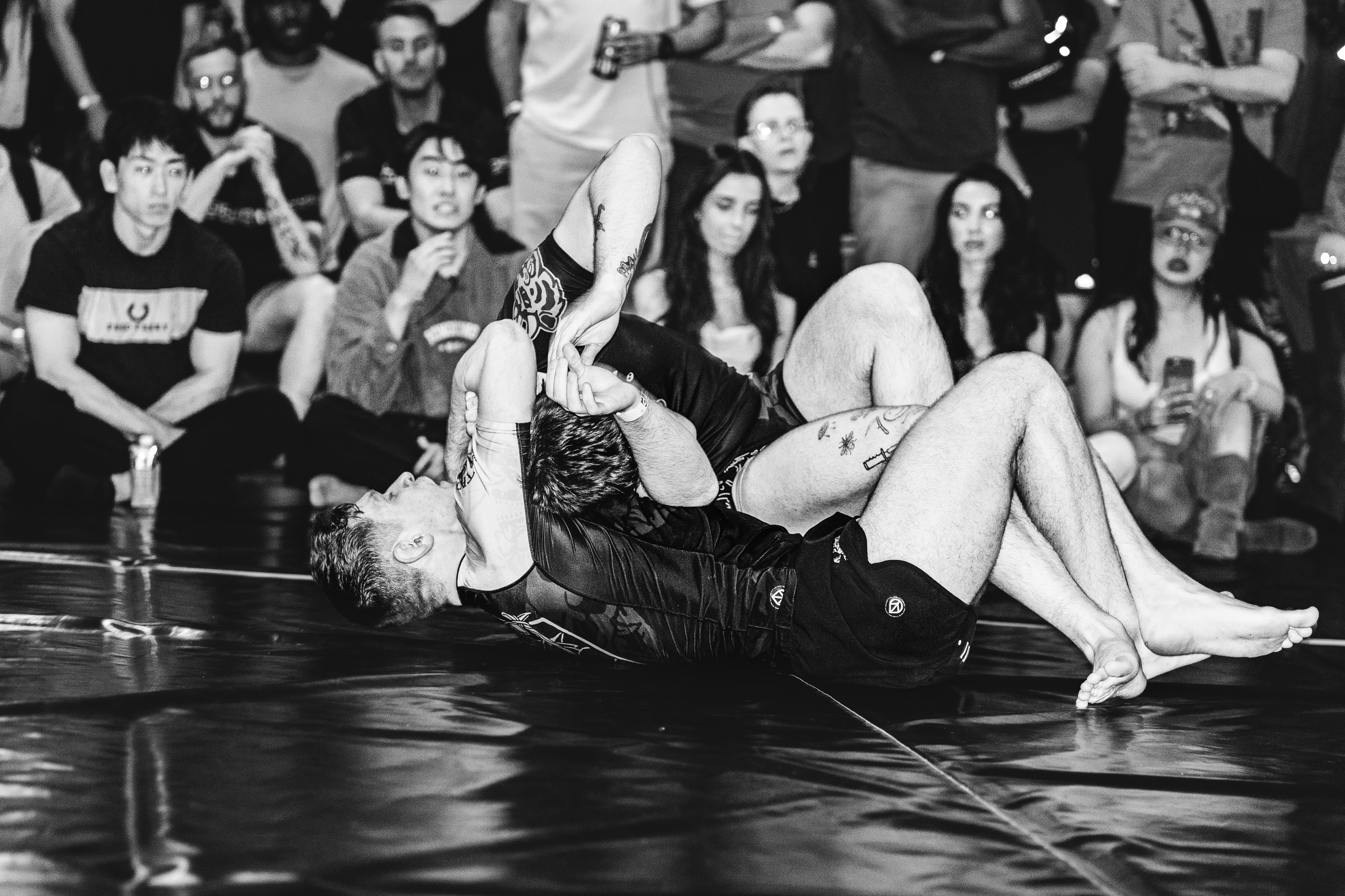Grounded Grapple: Two Fighters Lock in a Close Hinge on a Packed Mat