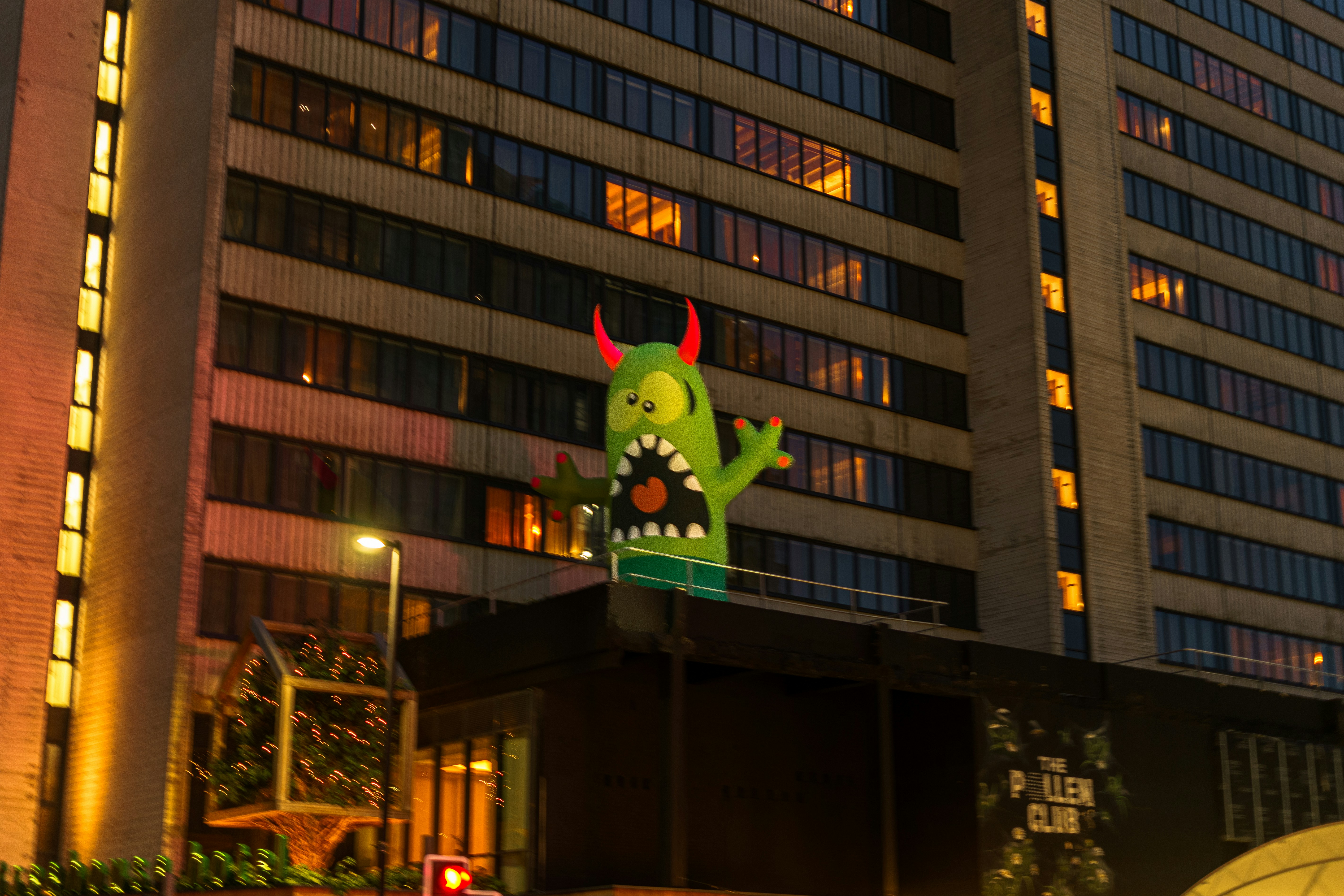 Nighttime Monster atop the City: A Neon-green Figure Guards the Building