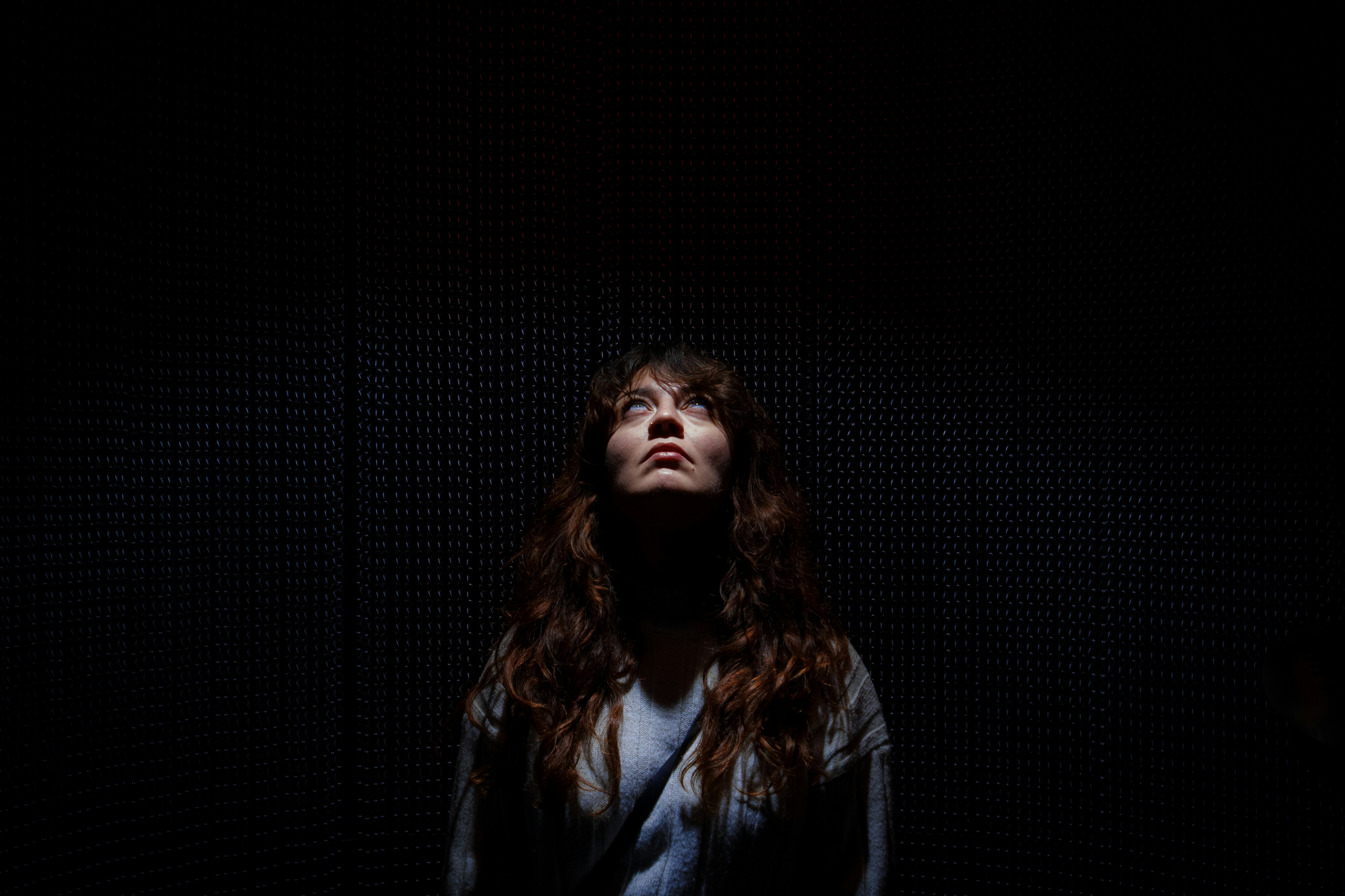 Under the single spotlight: a quiet gaze rises from the dark