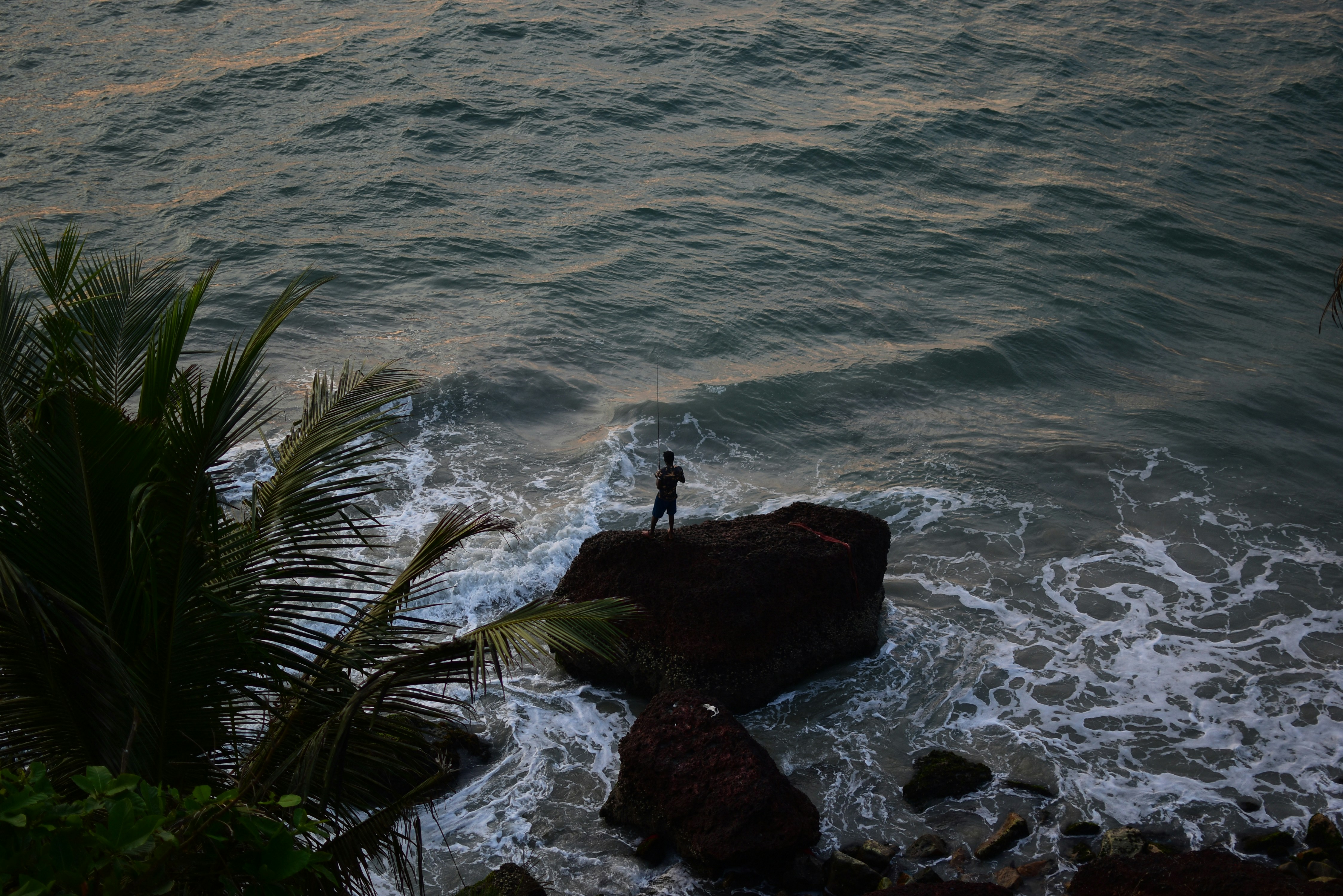  cliffside fisherman amid ocean breakers on a rocky outcrop