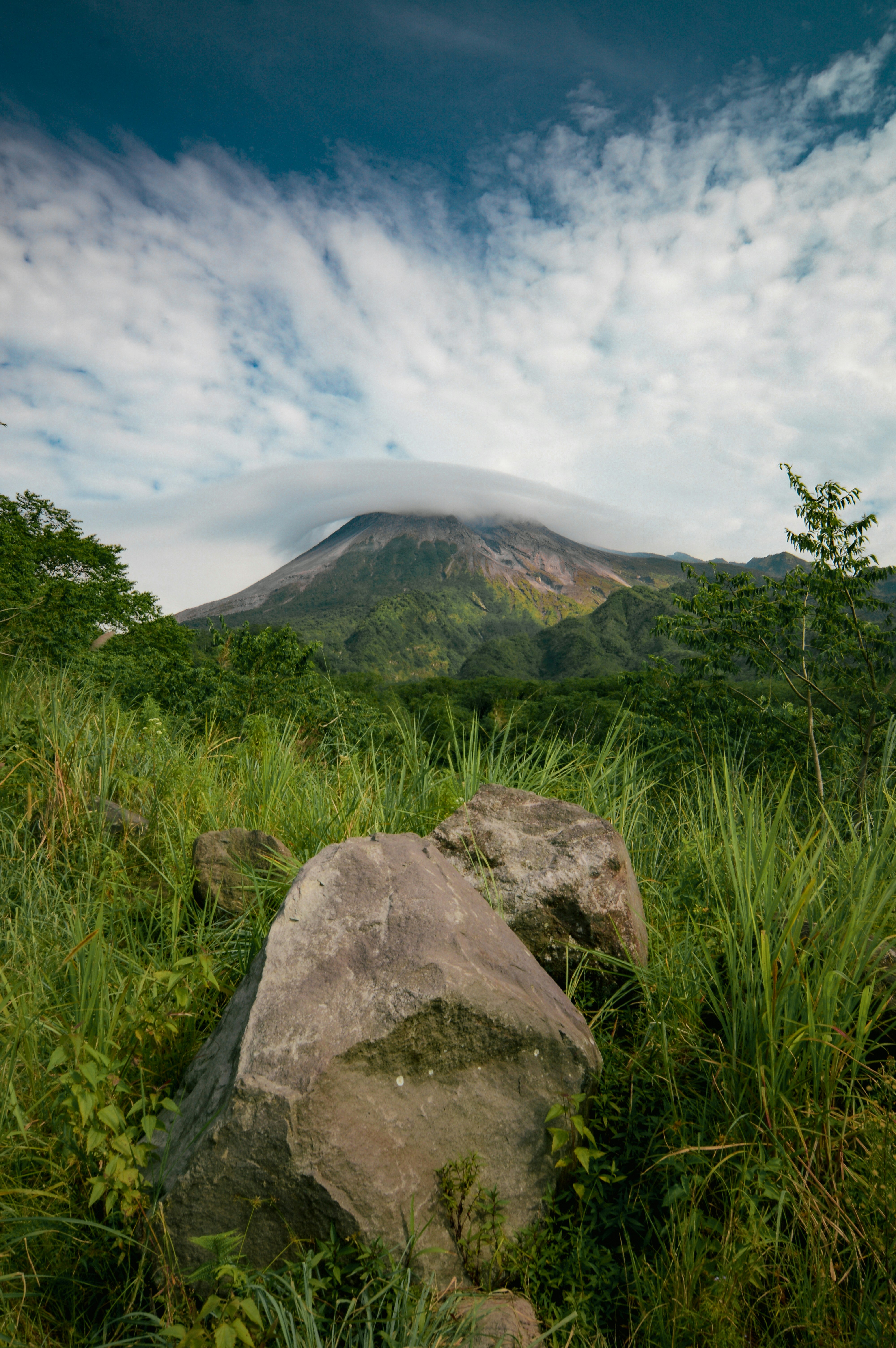 Cloud-ringed Volcano Rising Beyond a Quiet Field of Stones