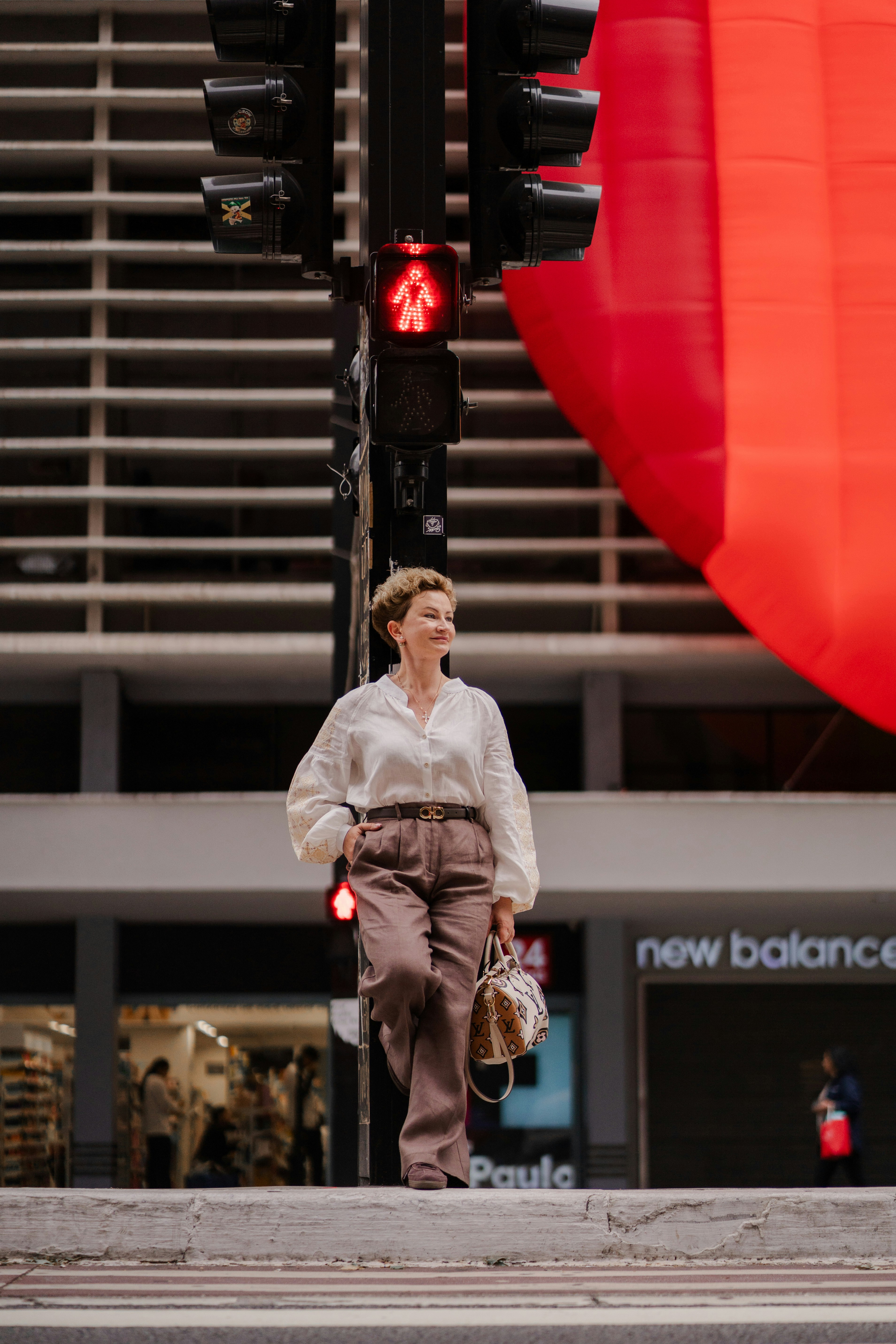 Urban stroll under neon red signals: a poised pedestrian amid storefronts