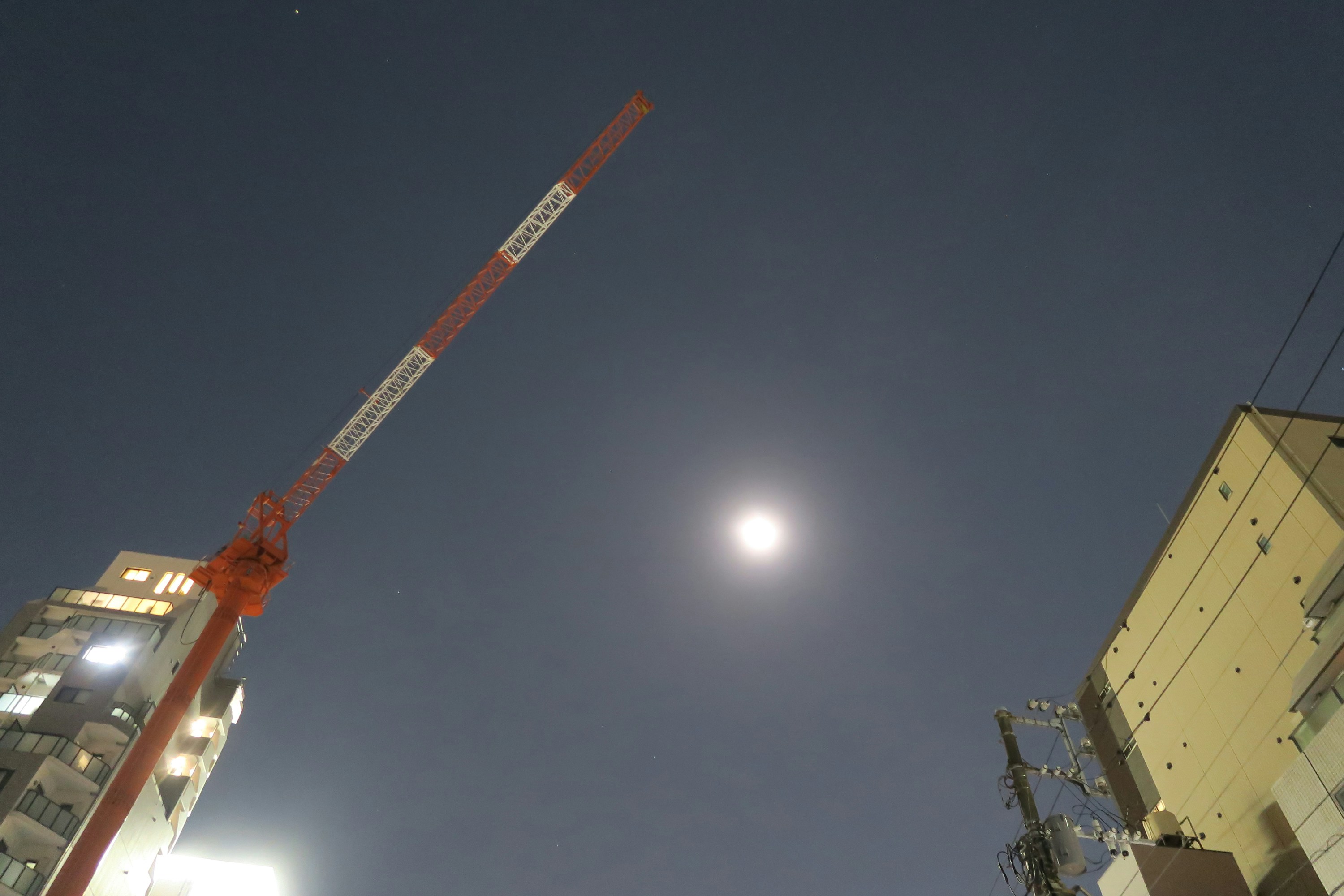 Moonlit construction: crane silhouette against a quiet night sky