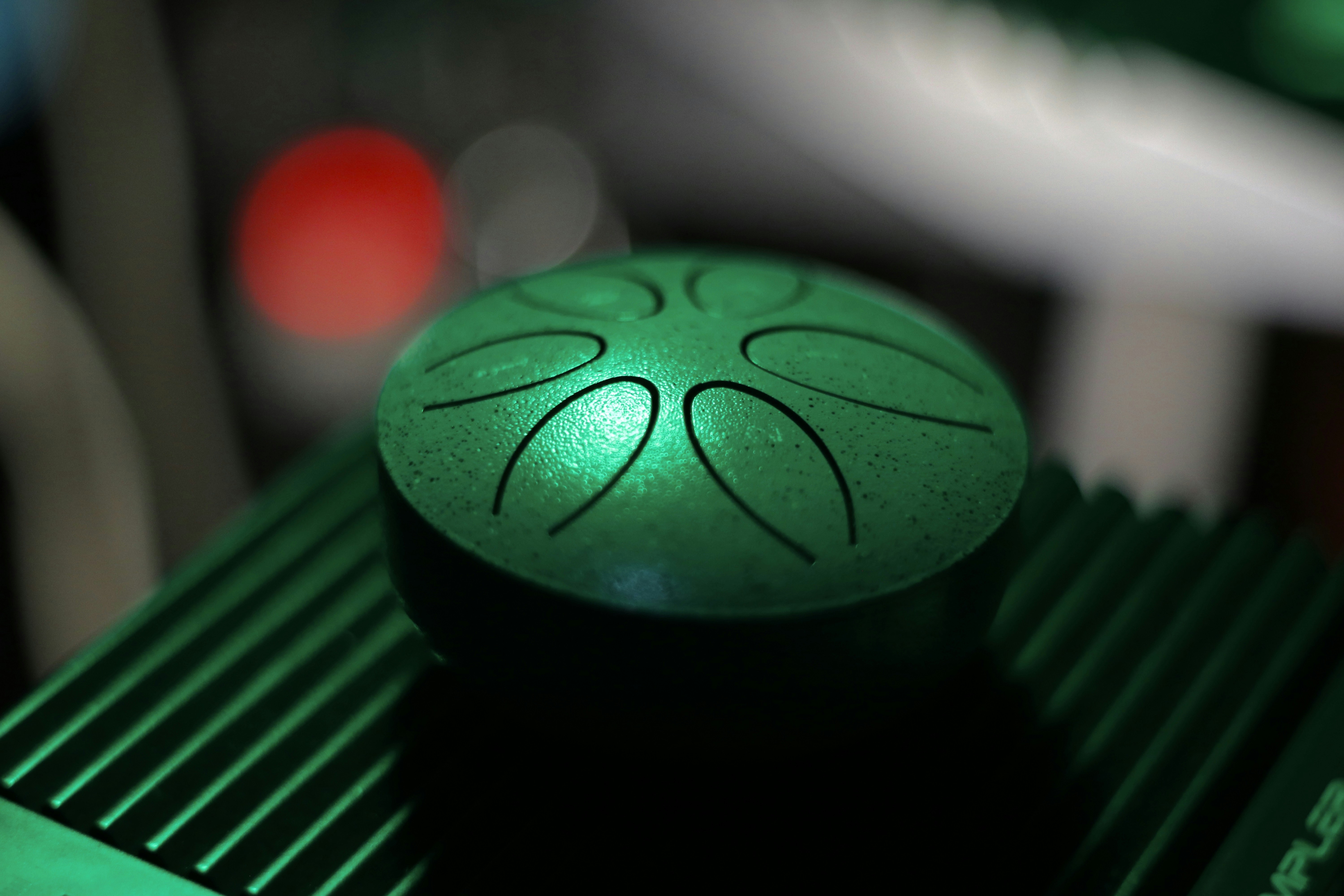 Steel tongue drum glowing with green light.