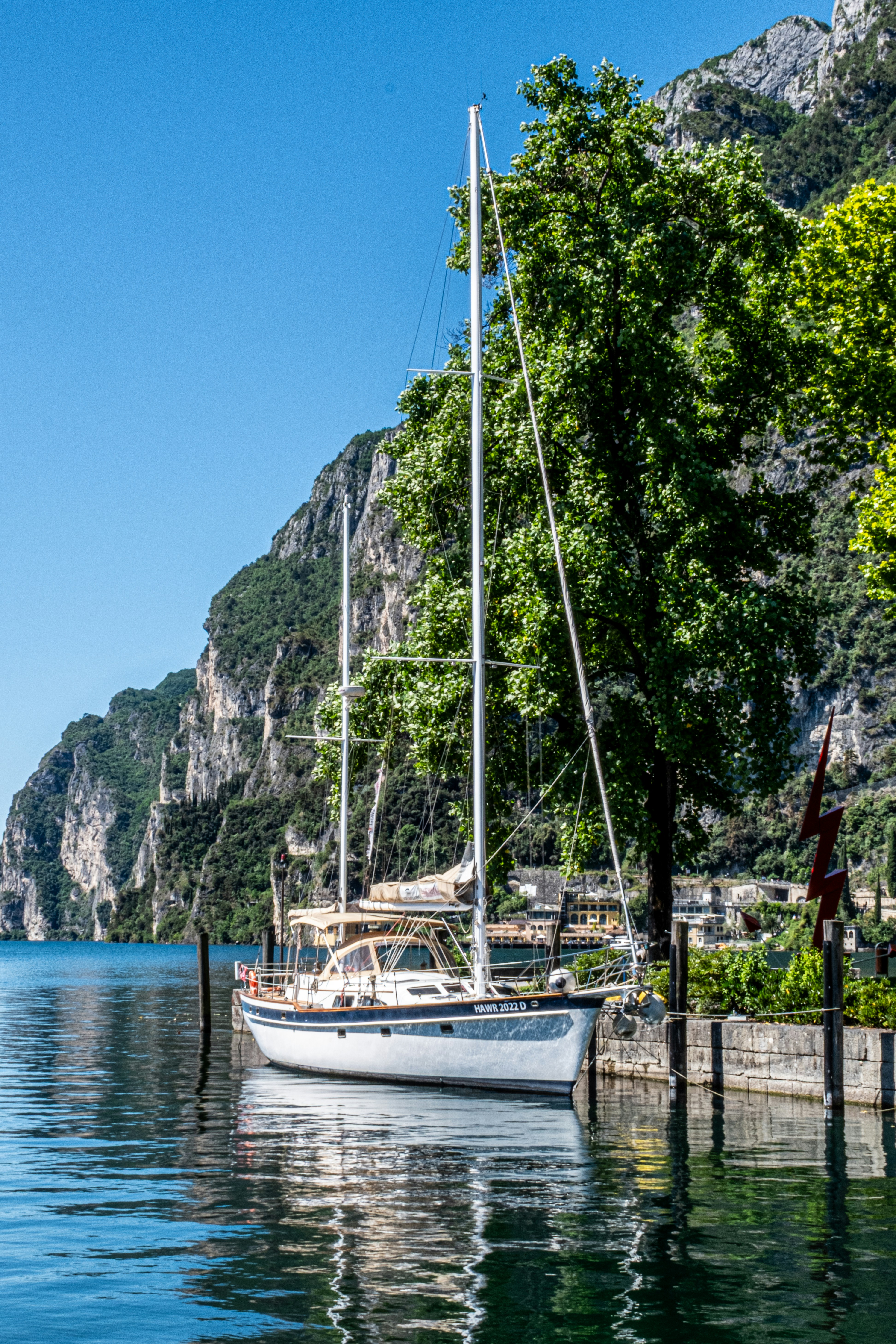 Sailboat Resting Along Verdant Lakefront Under Alpine Canopy