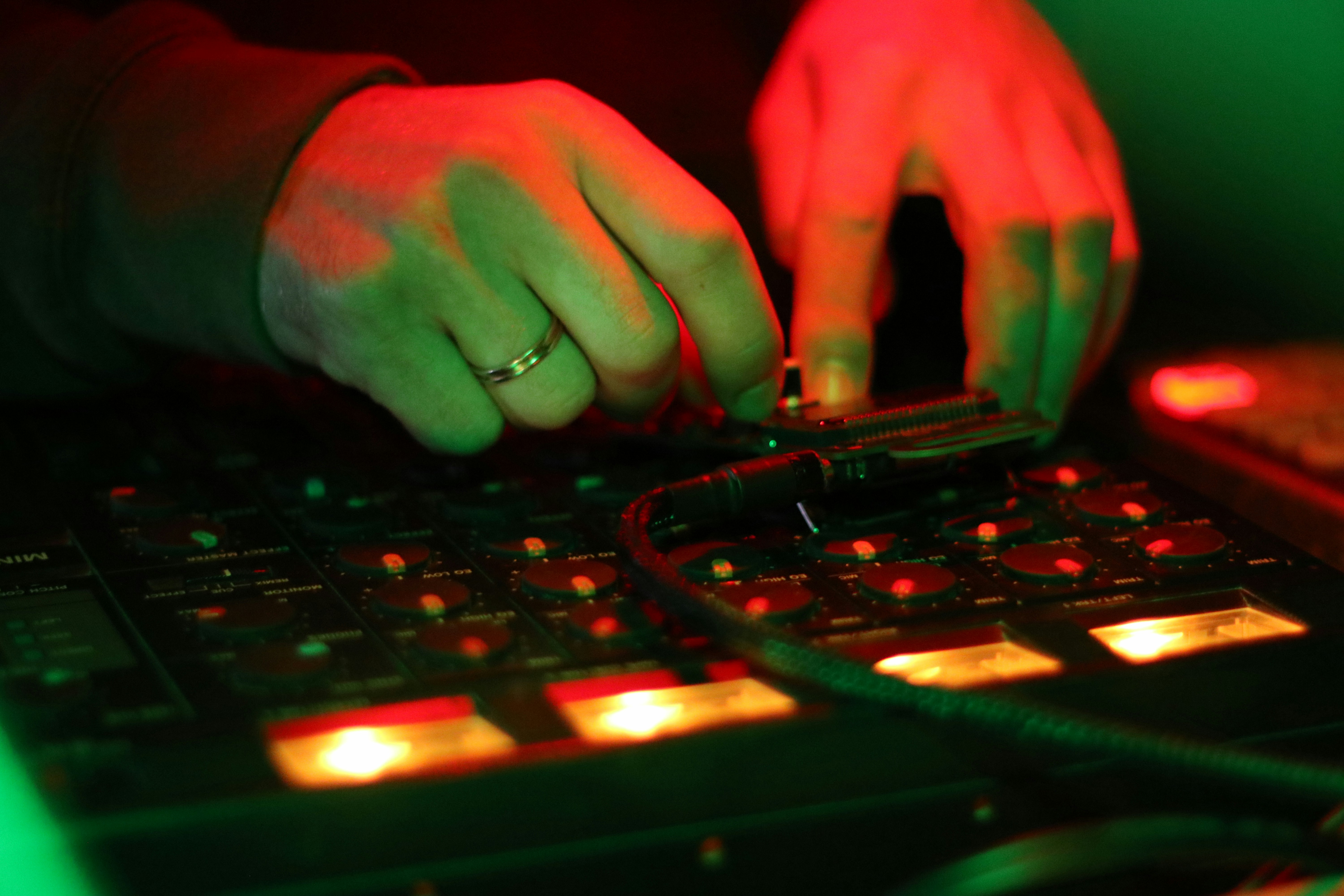 A close-up shot of hands adjusting settings on an audio mixer during a live music performance.
