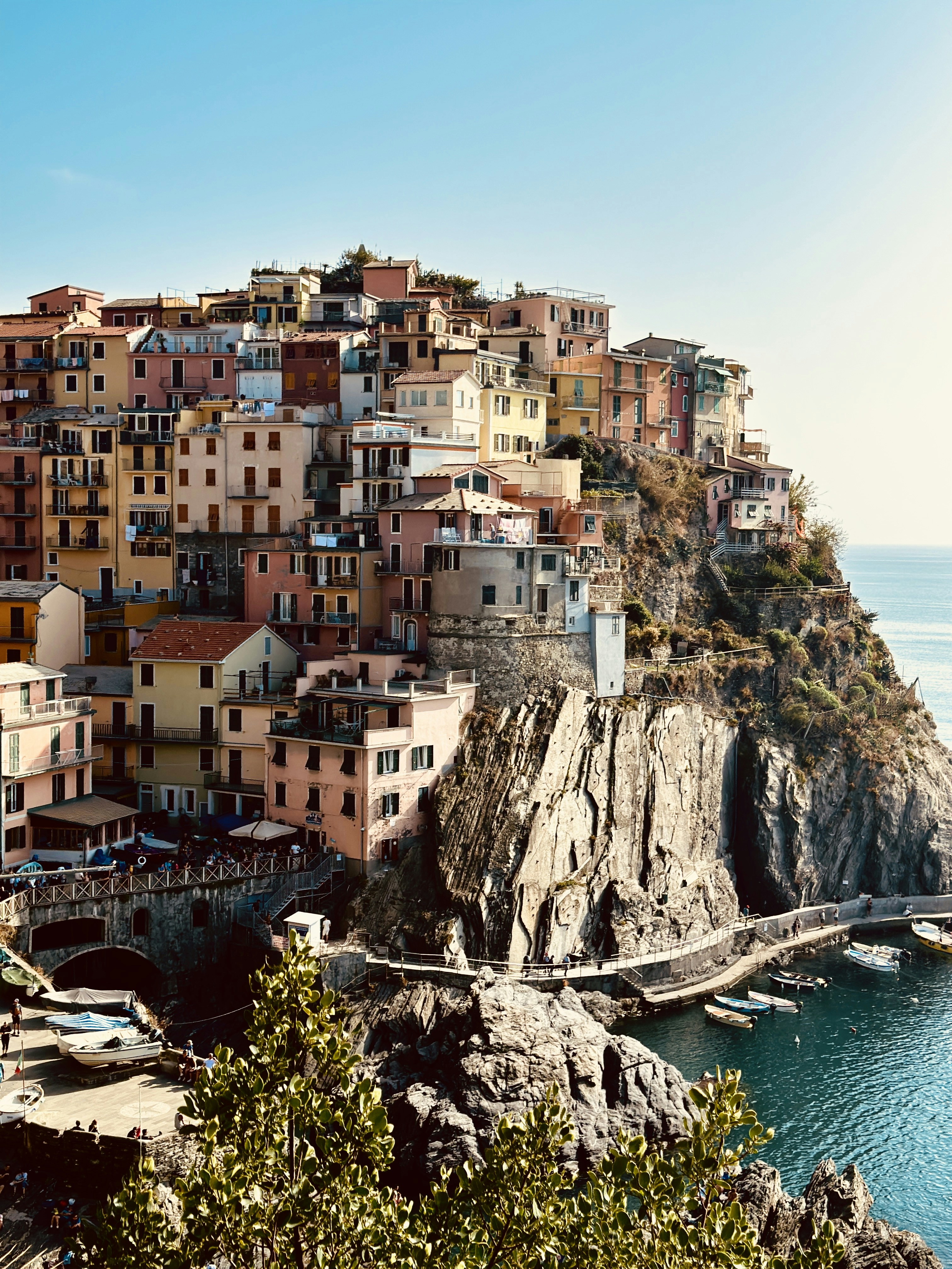 Colorful cliffside village stacked on sunlit cliffs above a quiet harbor