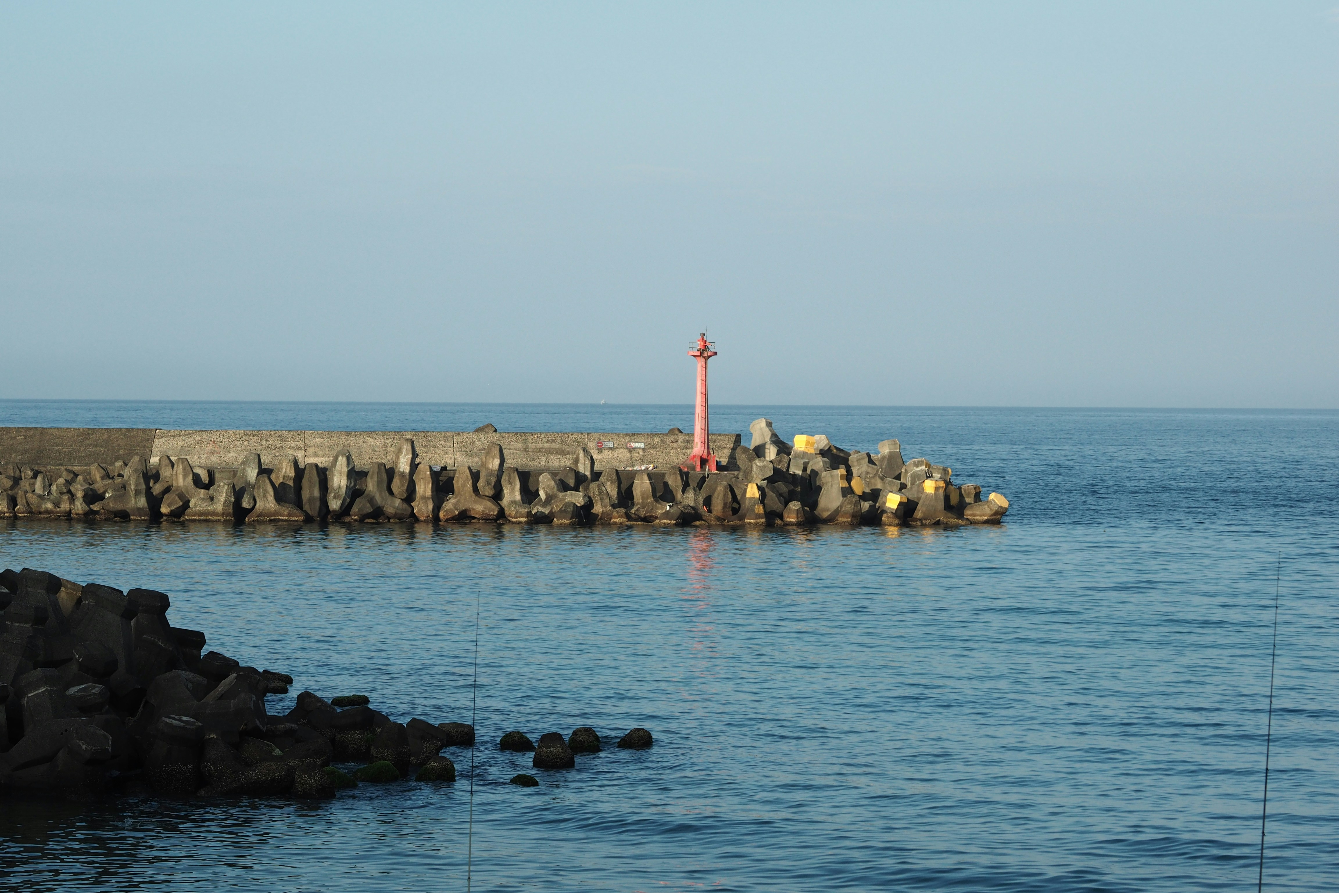 Red Lighthouse at the Breakwater: Calm Seas, Quiet Horizon