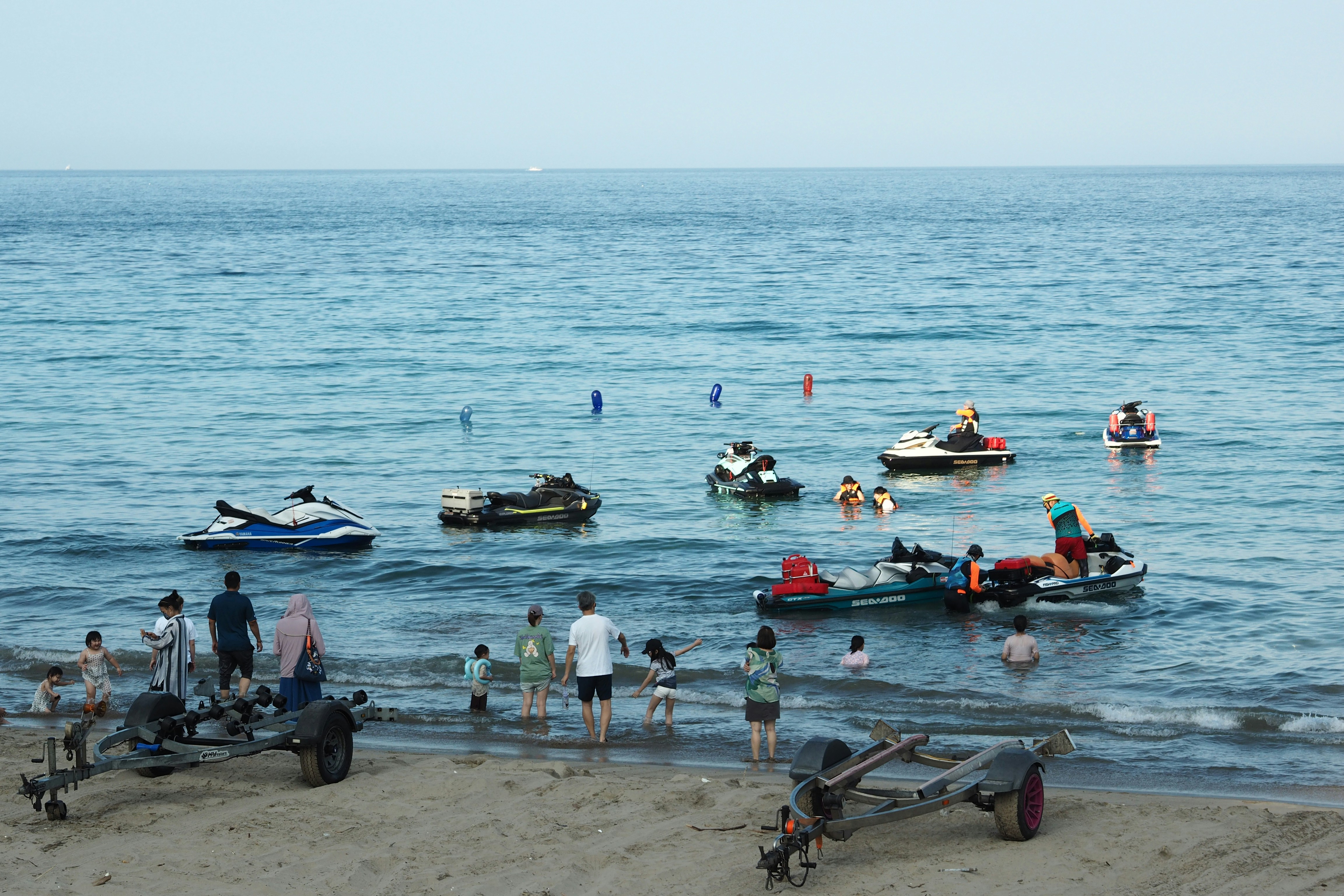 Sunlit Beachfront Scene with Boats and Playful Crowd