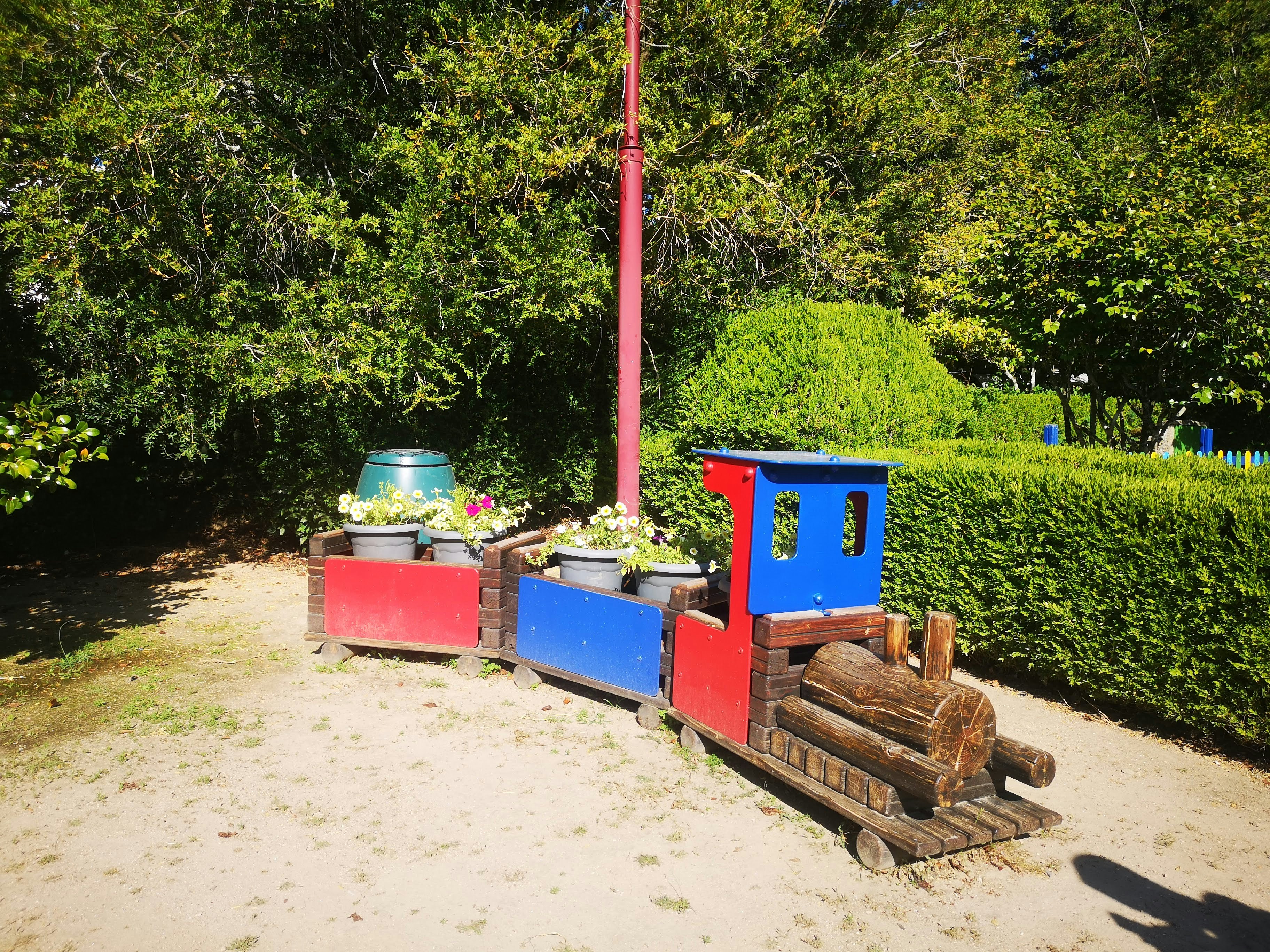 A colorful wooden toy train with flowers in a park.