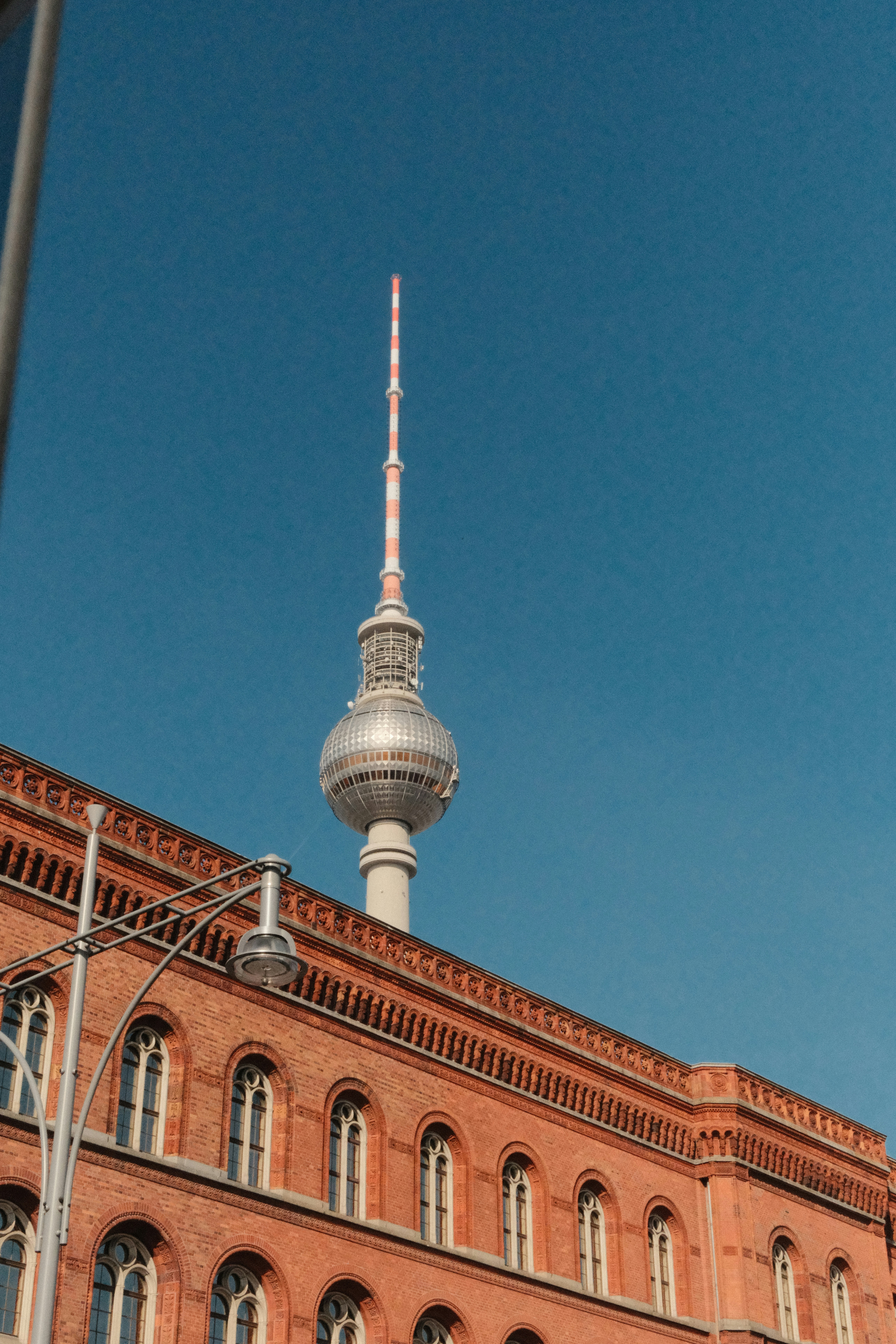 Skyline Sentinel: Berlin TV Tower Reaching Over Brick Facades