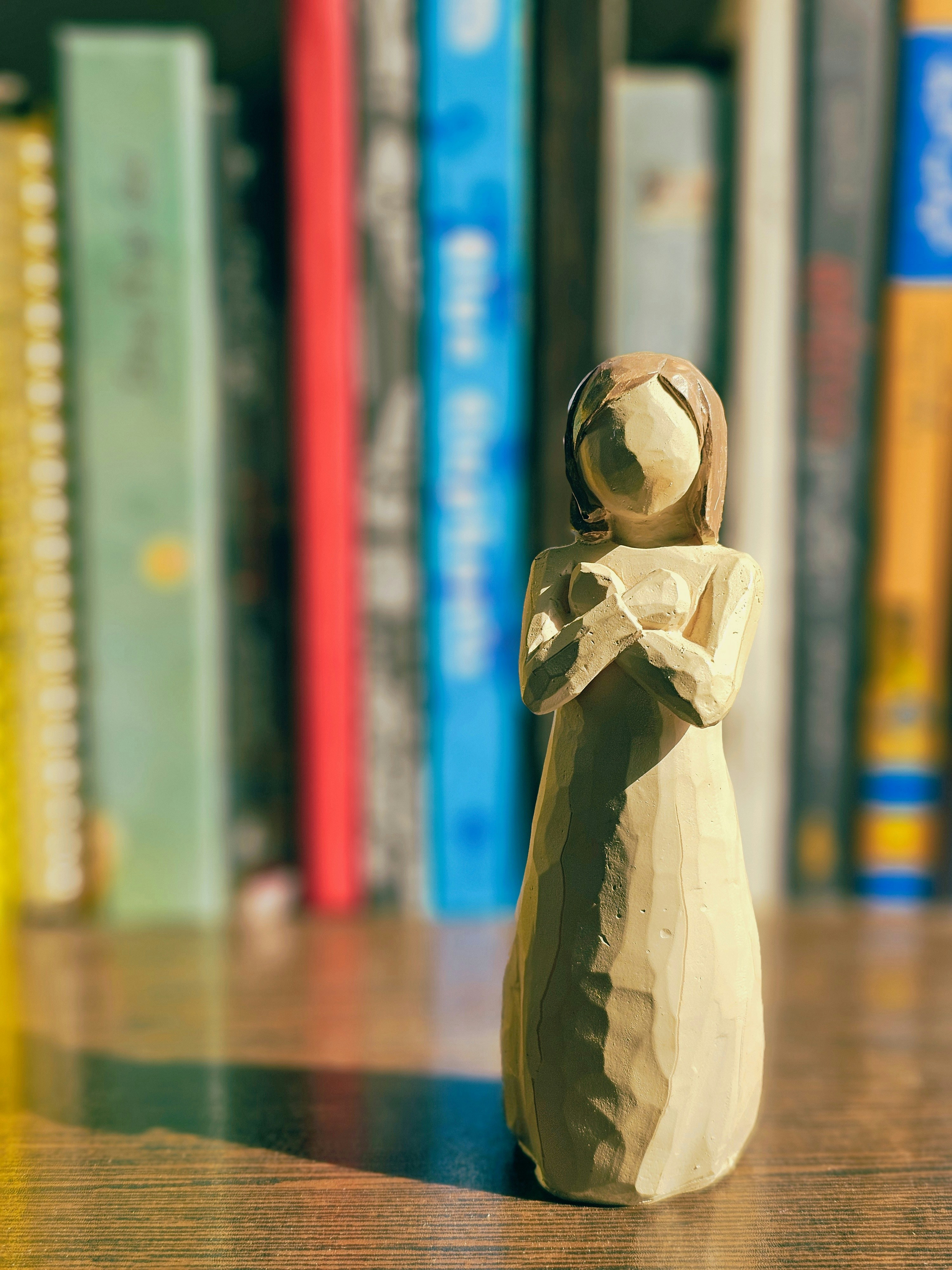 Silhouette of Hope: A Tiny Carved Figure Against a Wall of Books