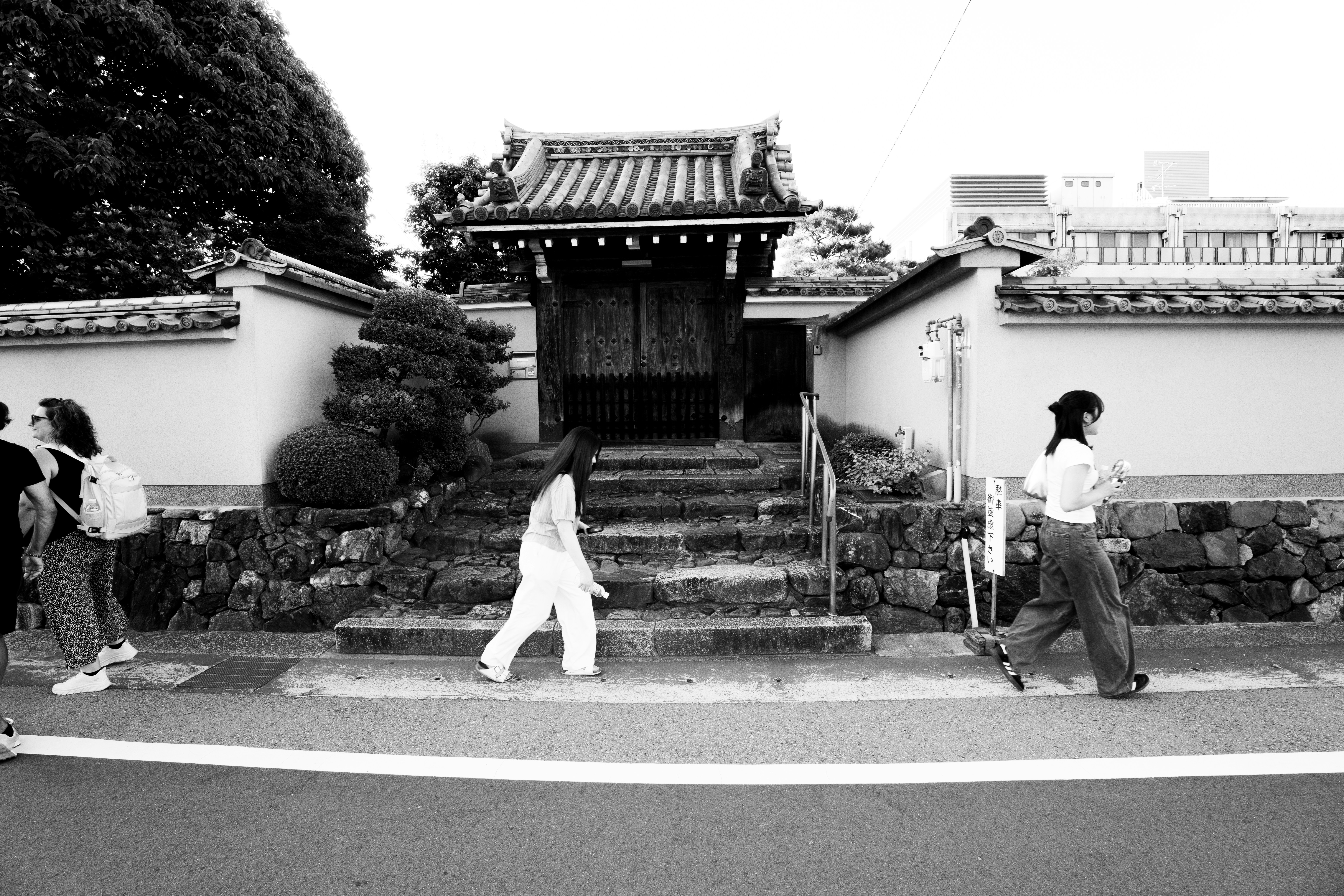 Pedestrians walk past a traditional japanese temple gate.