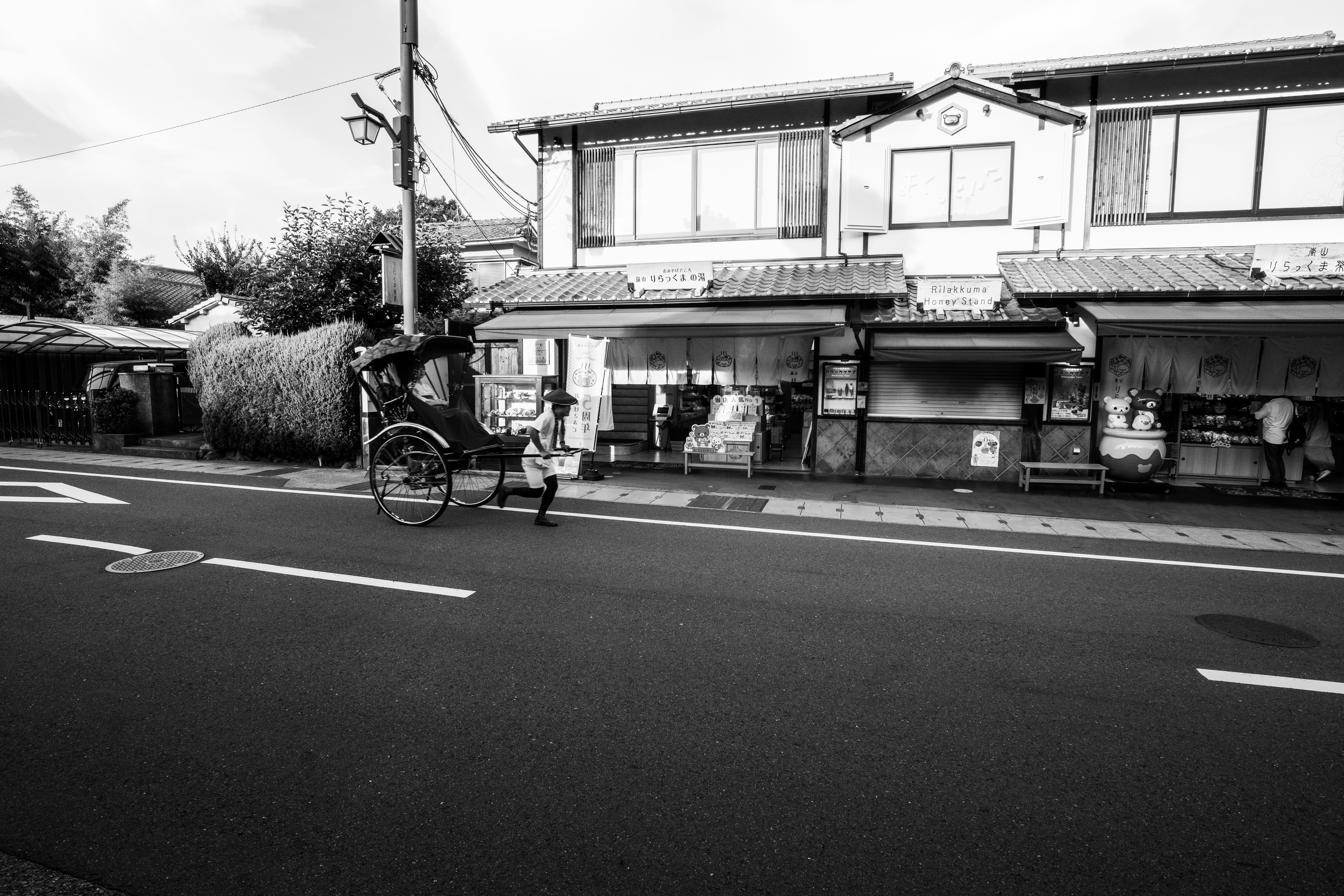 A person pulls a rickshaw past buildings on a street.