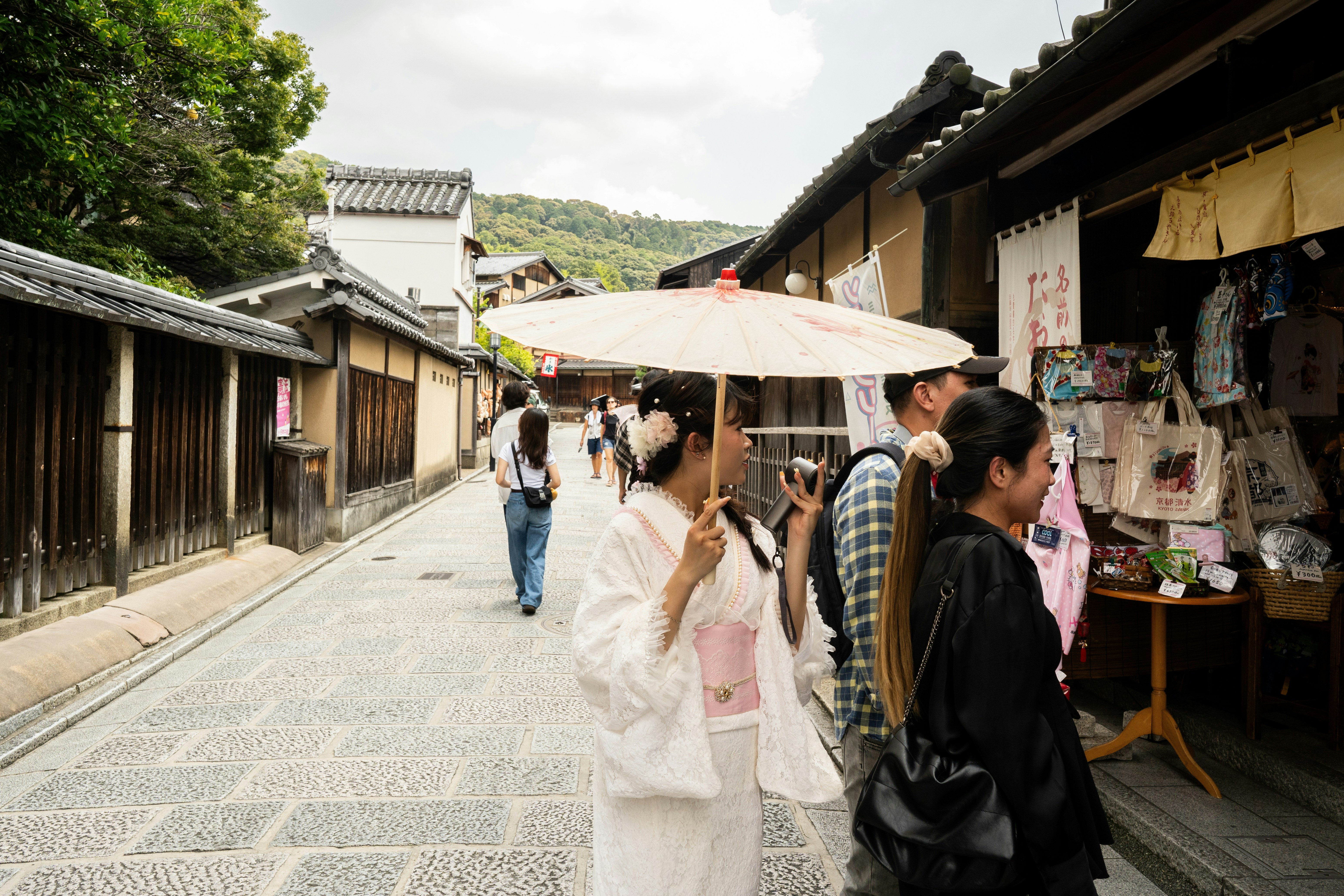 Woman in kimono with parasol walks on a traditional street.