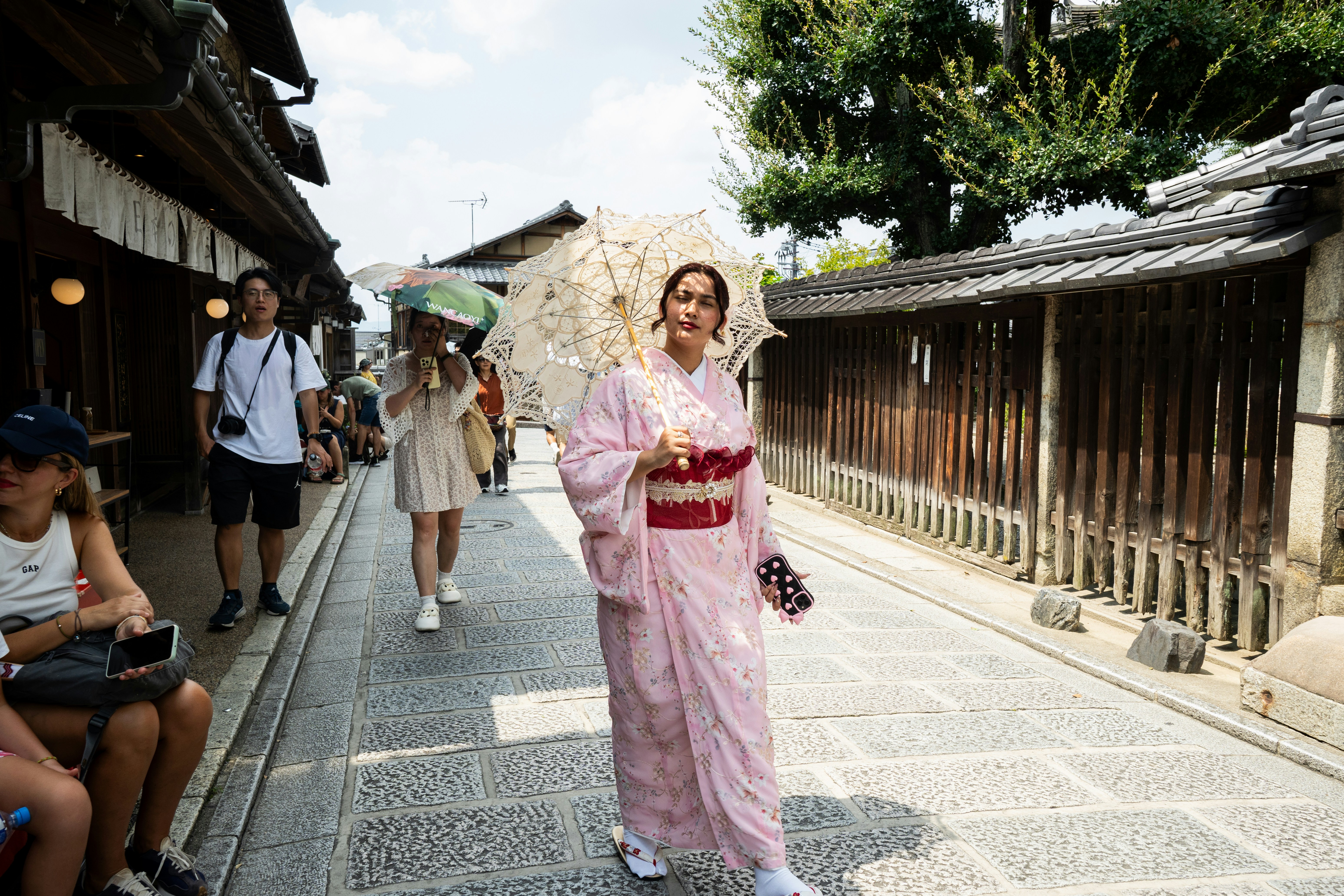 A Geisha in Pink Amid Narrow Kyoto Street
