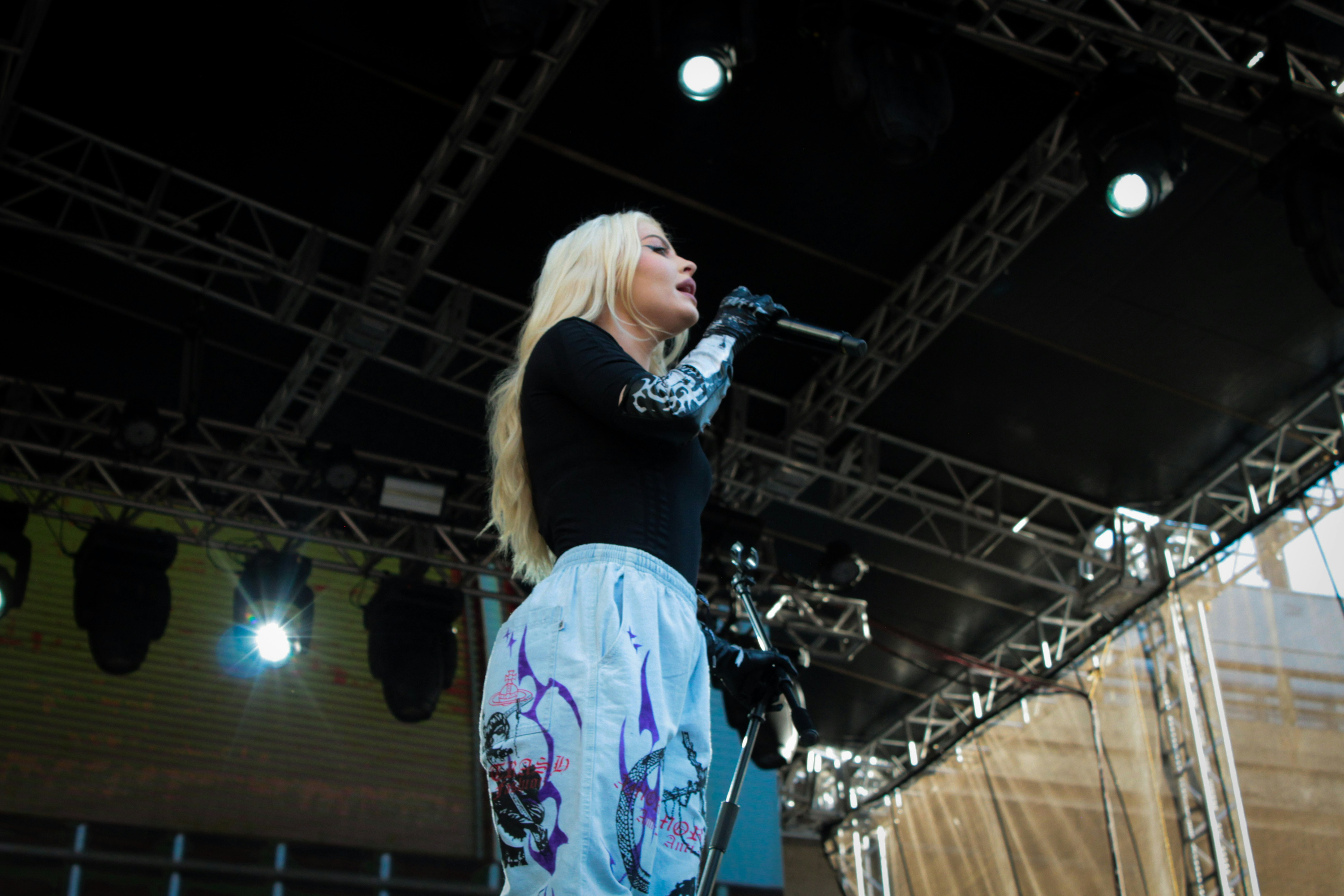 A blonde woman sings into a microphone on stage.