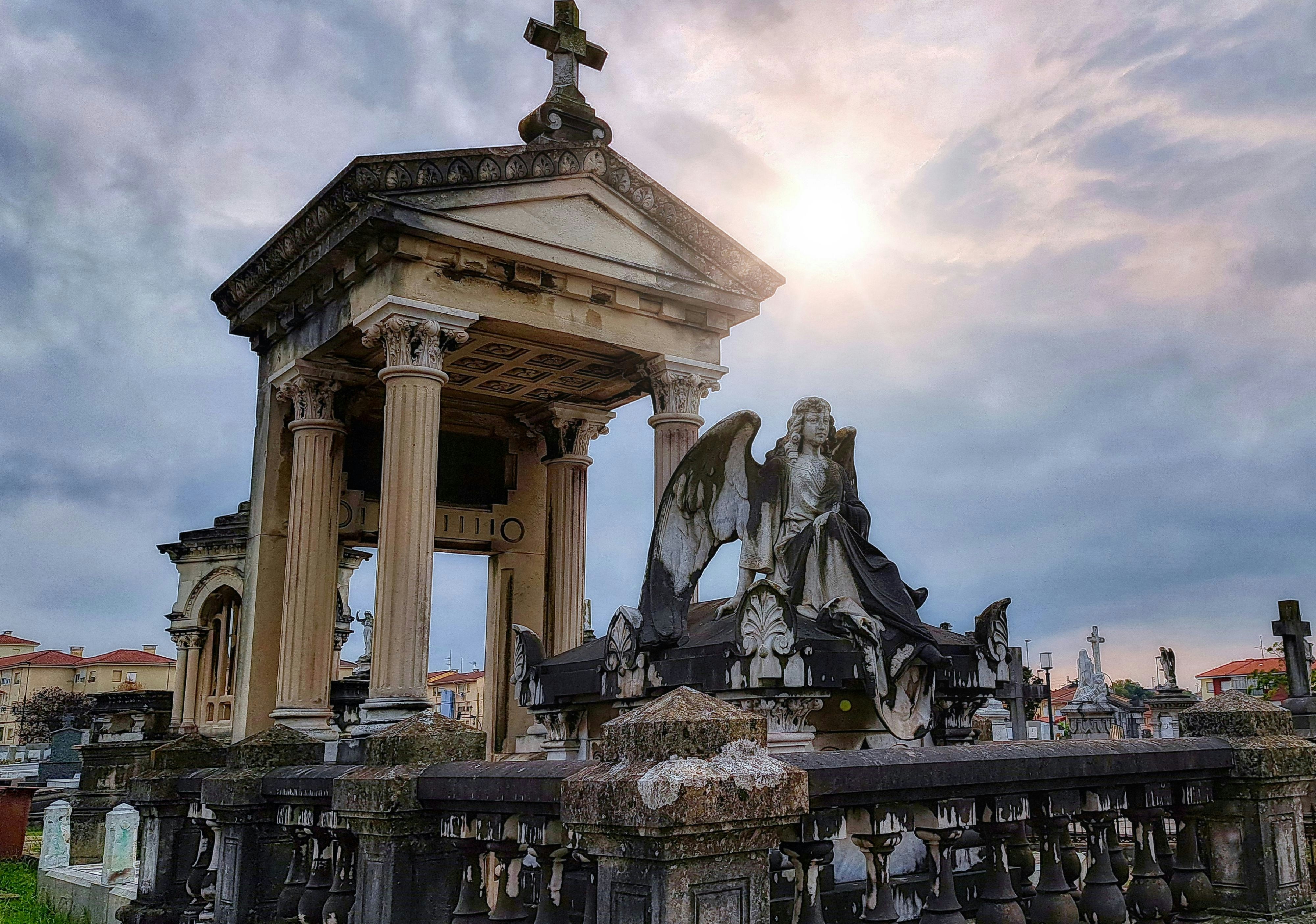 Cemetery monument and statue under a sunlit pediment