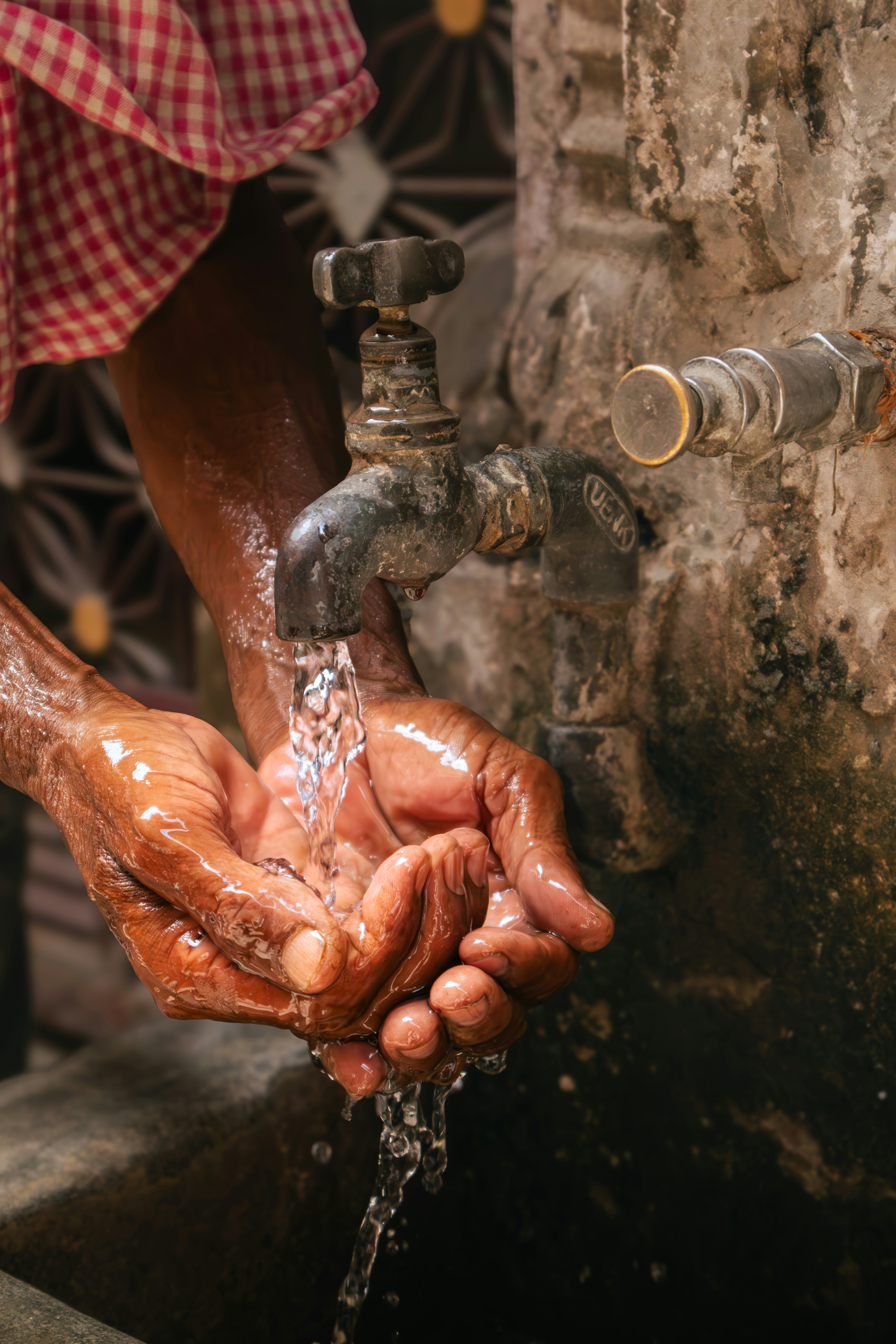 A poor laborer man washing his hands with tap water during the harsh Indian summers.