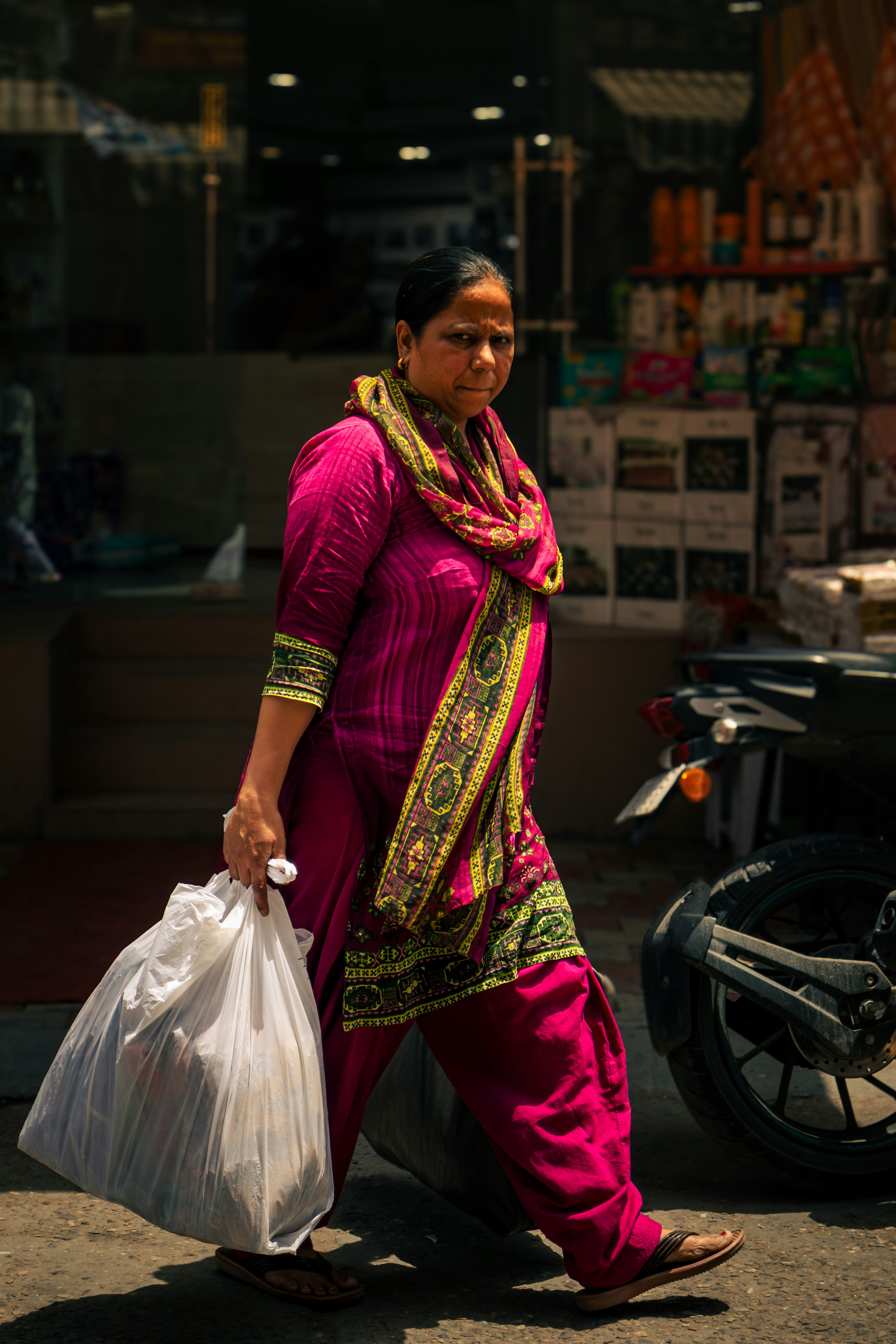 Woman walking with plastic bags in her hands during the harsh Indian summers.