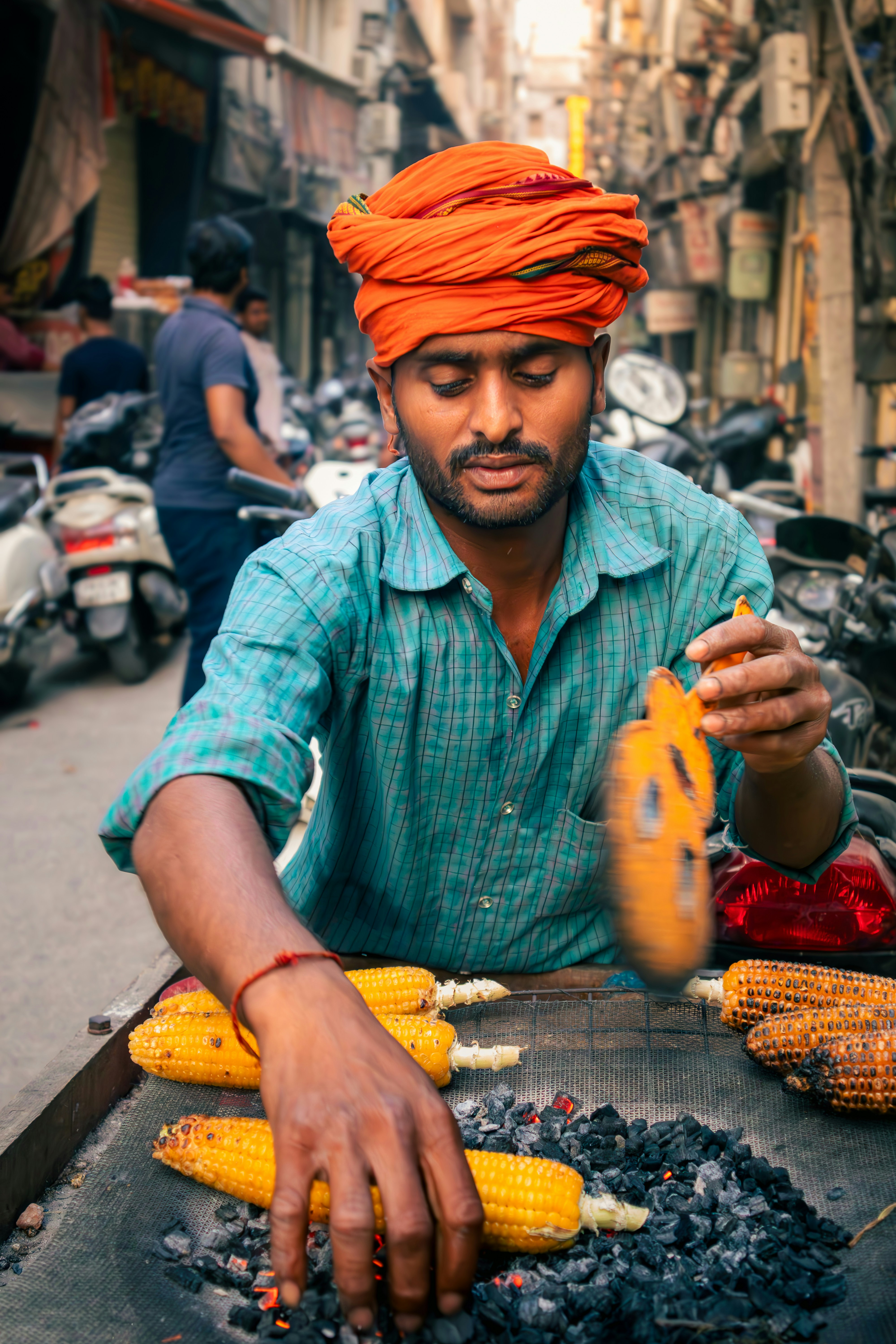 Hands at the Grill: A Vendor Preparing Golden Corn under an Orange Turban