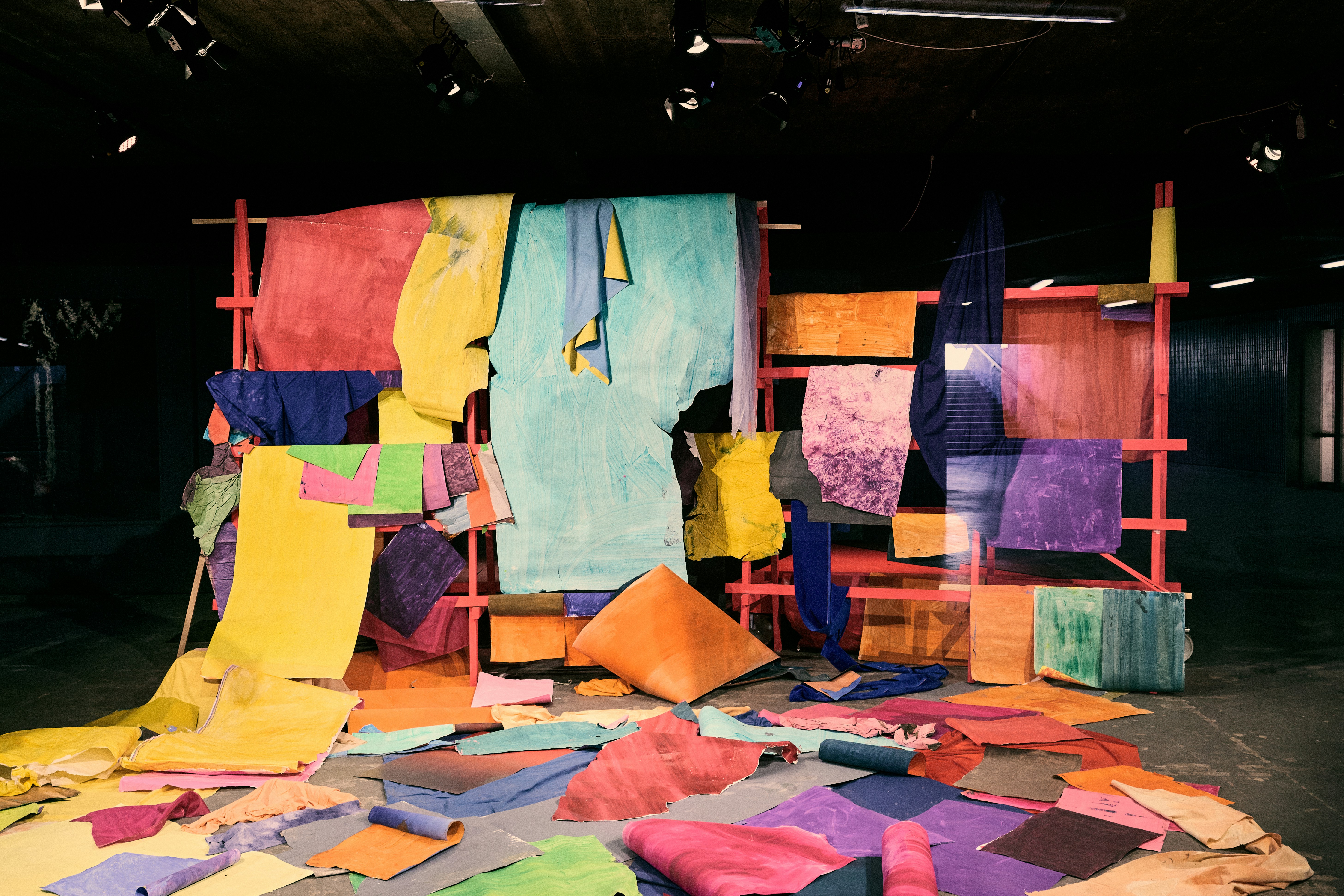 Colorful fabric art installation with textiles draped and scattered.