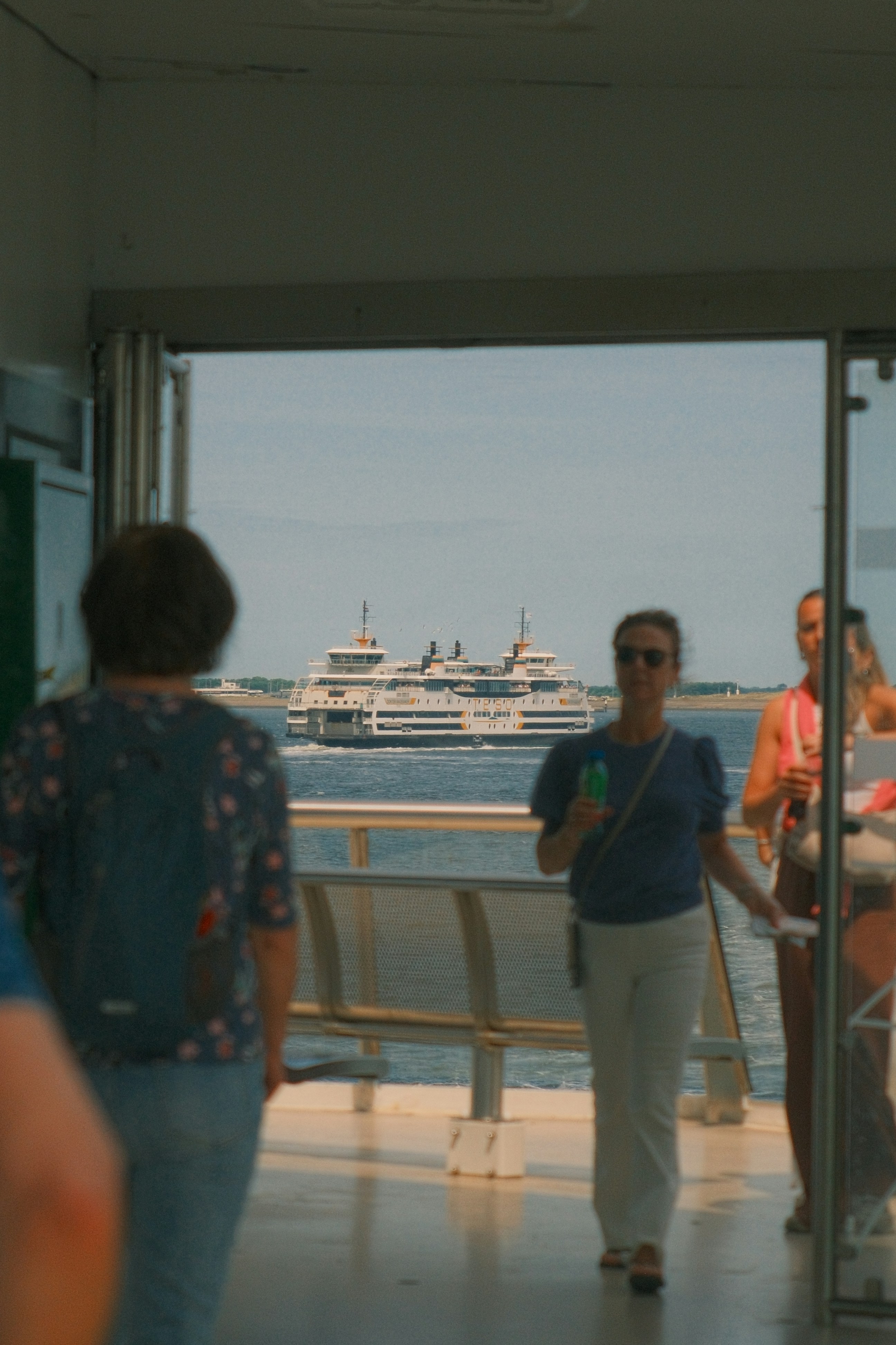  Ferry Stop: Passengers Pausing as a Yacht Laps the Horizon