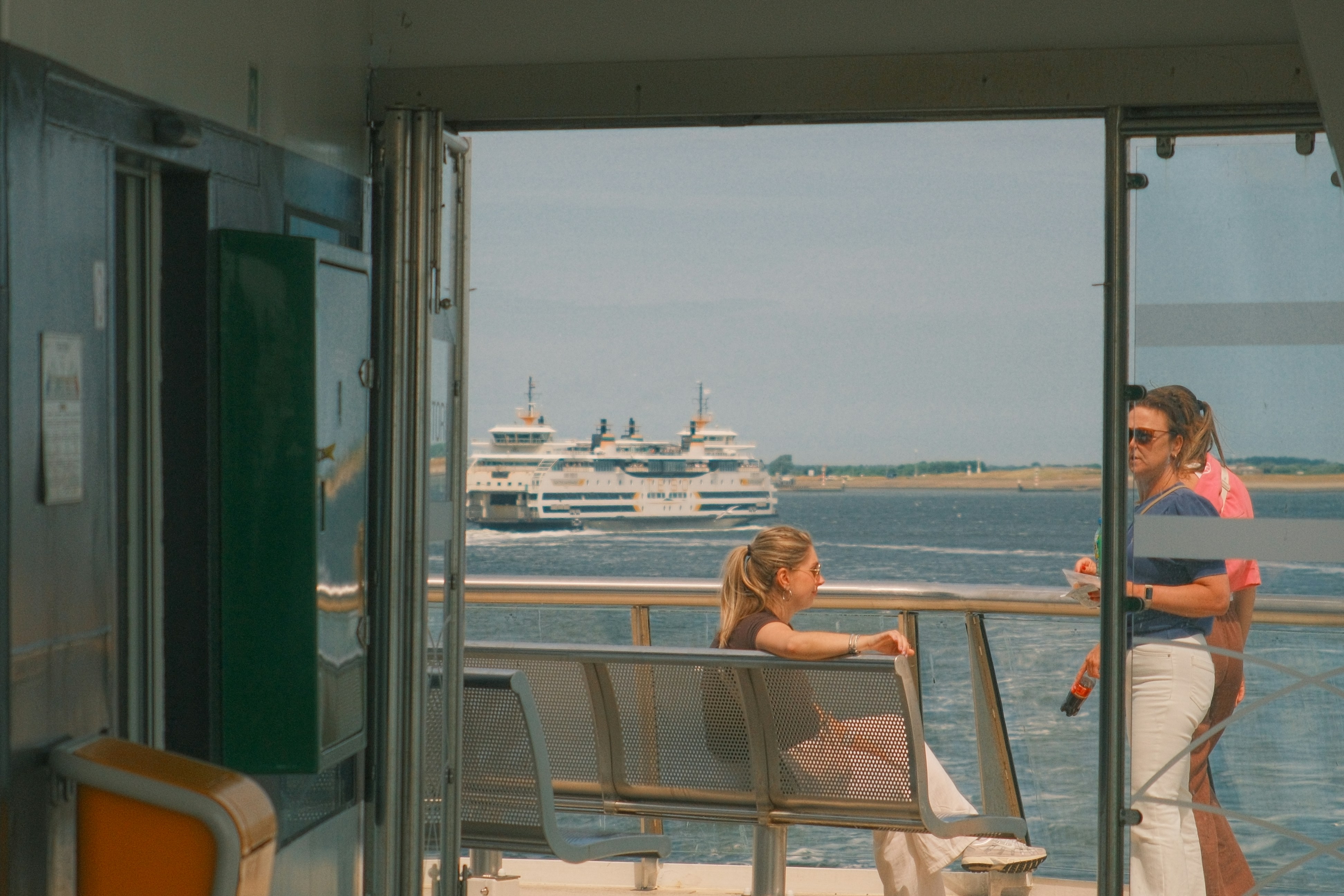 Two people on a ferry deck watching another ferry pass.