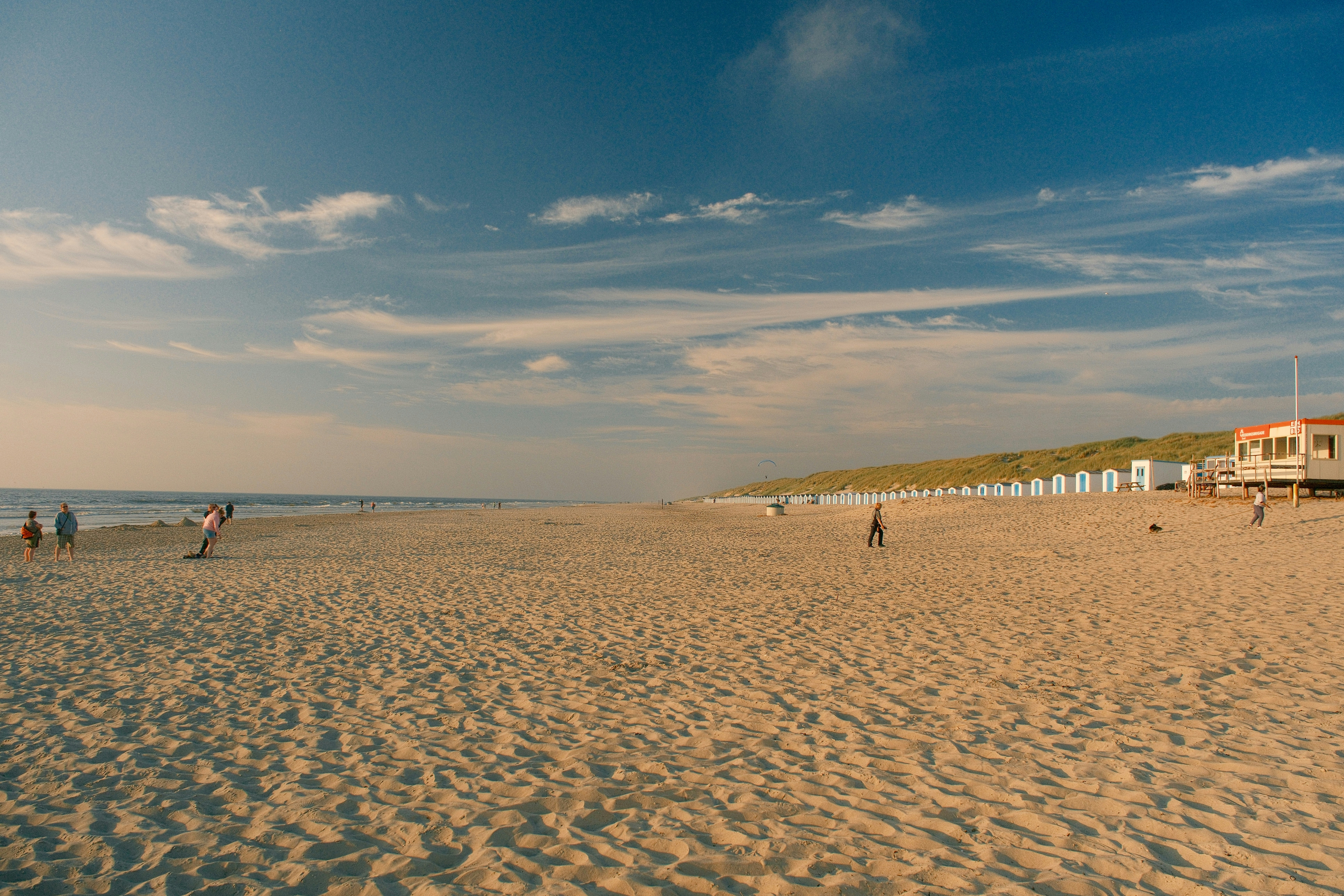 Sunny day on a wide sandy beach with beach huts.