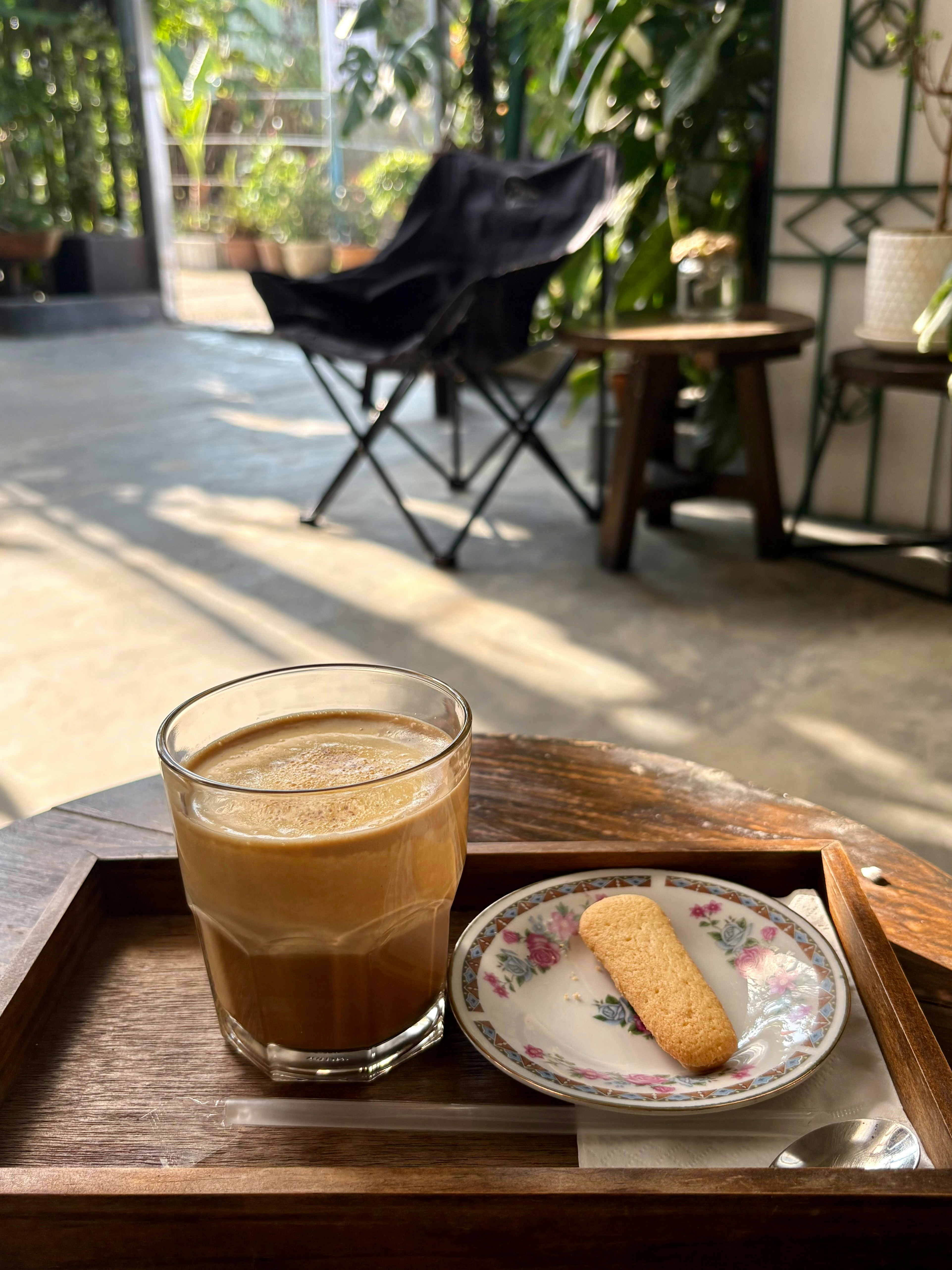 Cafe Tray Calm: Coffee and Biscuit on a Wooden Tray in Soft-Backlit Patio